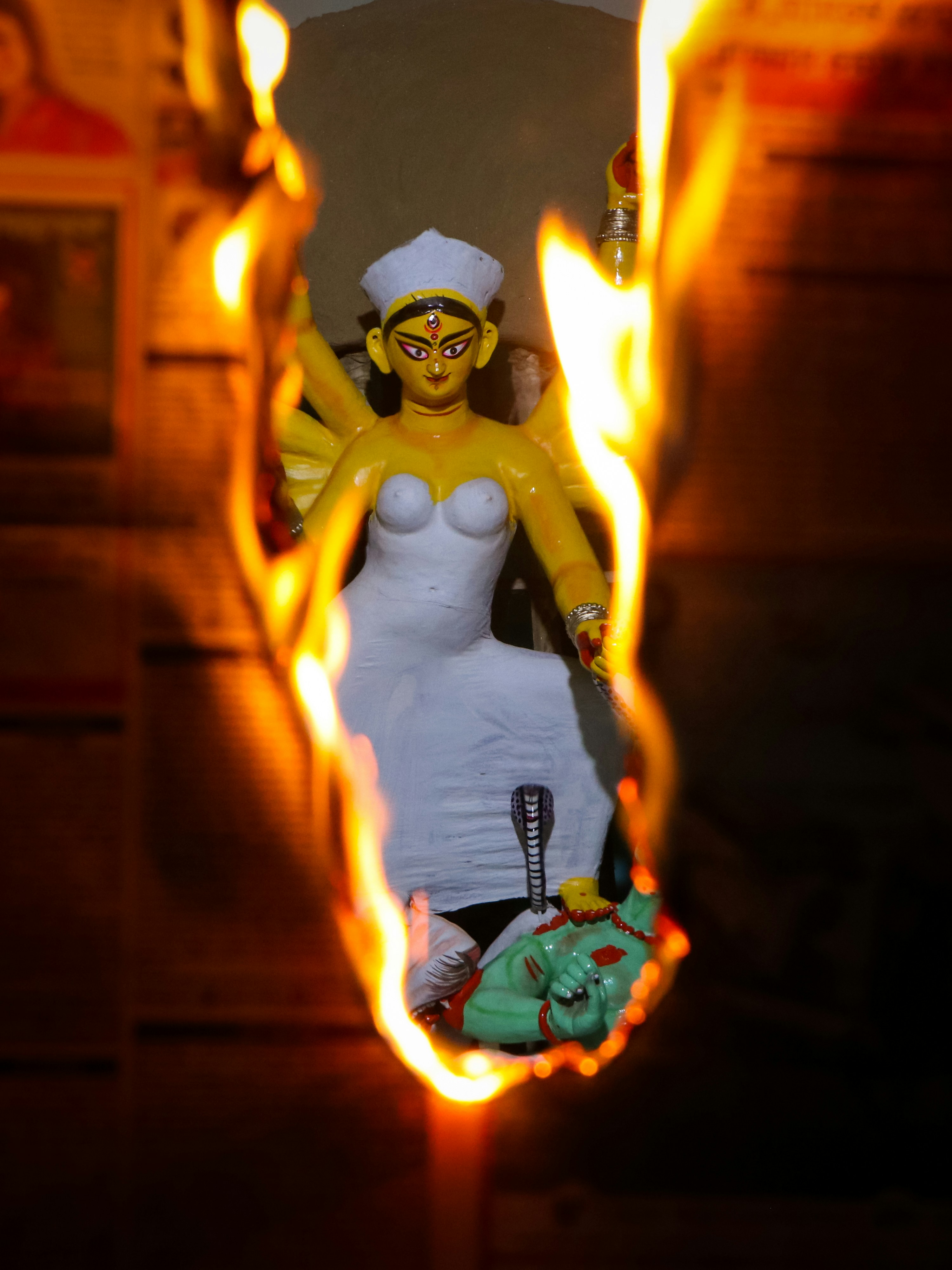 Flame-Framed Idol: A Candlelit Statue Nestled Between Fire Arches