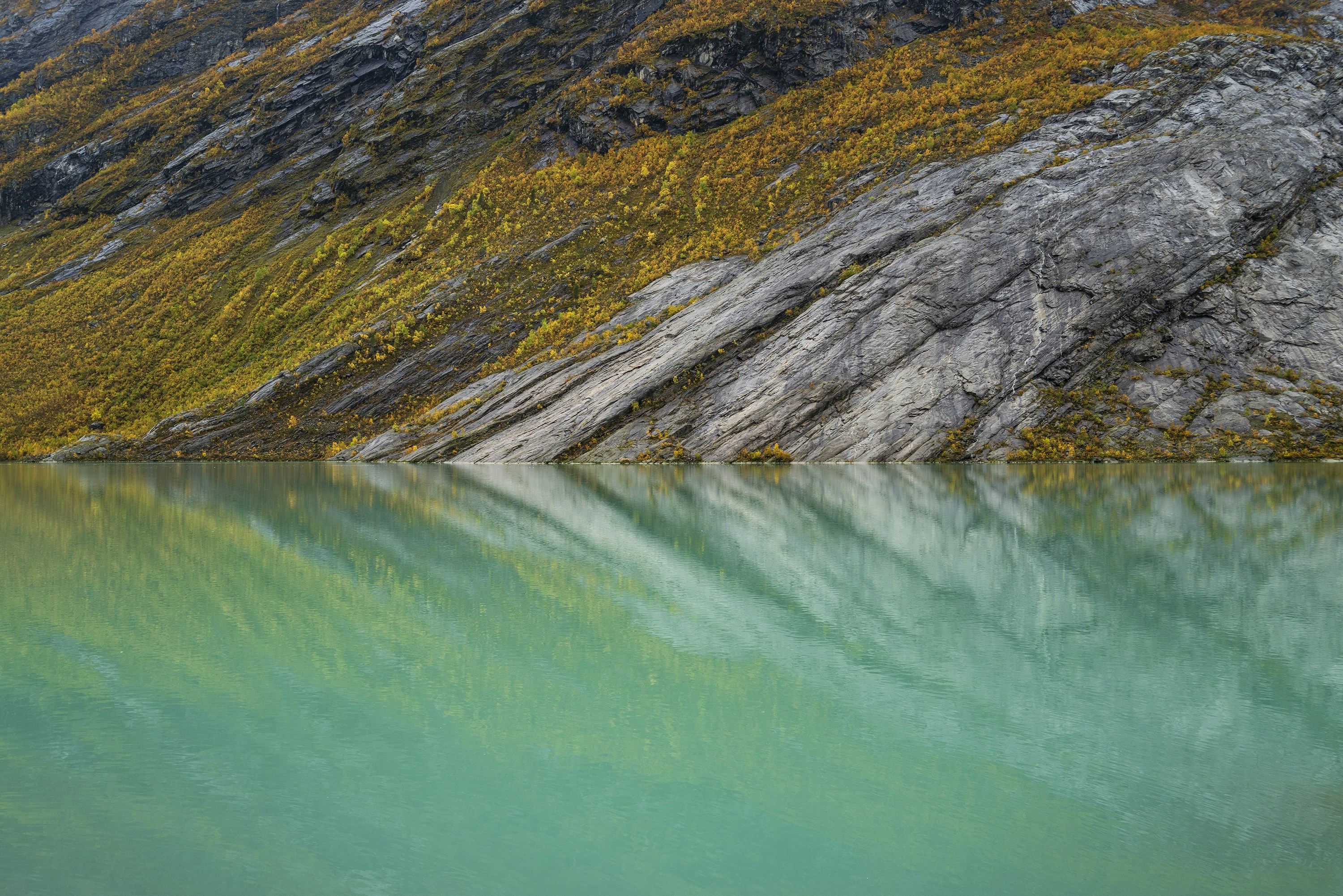 Emerald Fjord Meets Striated Ridge in Autumn Light