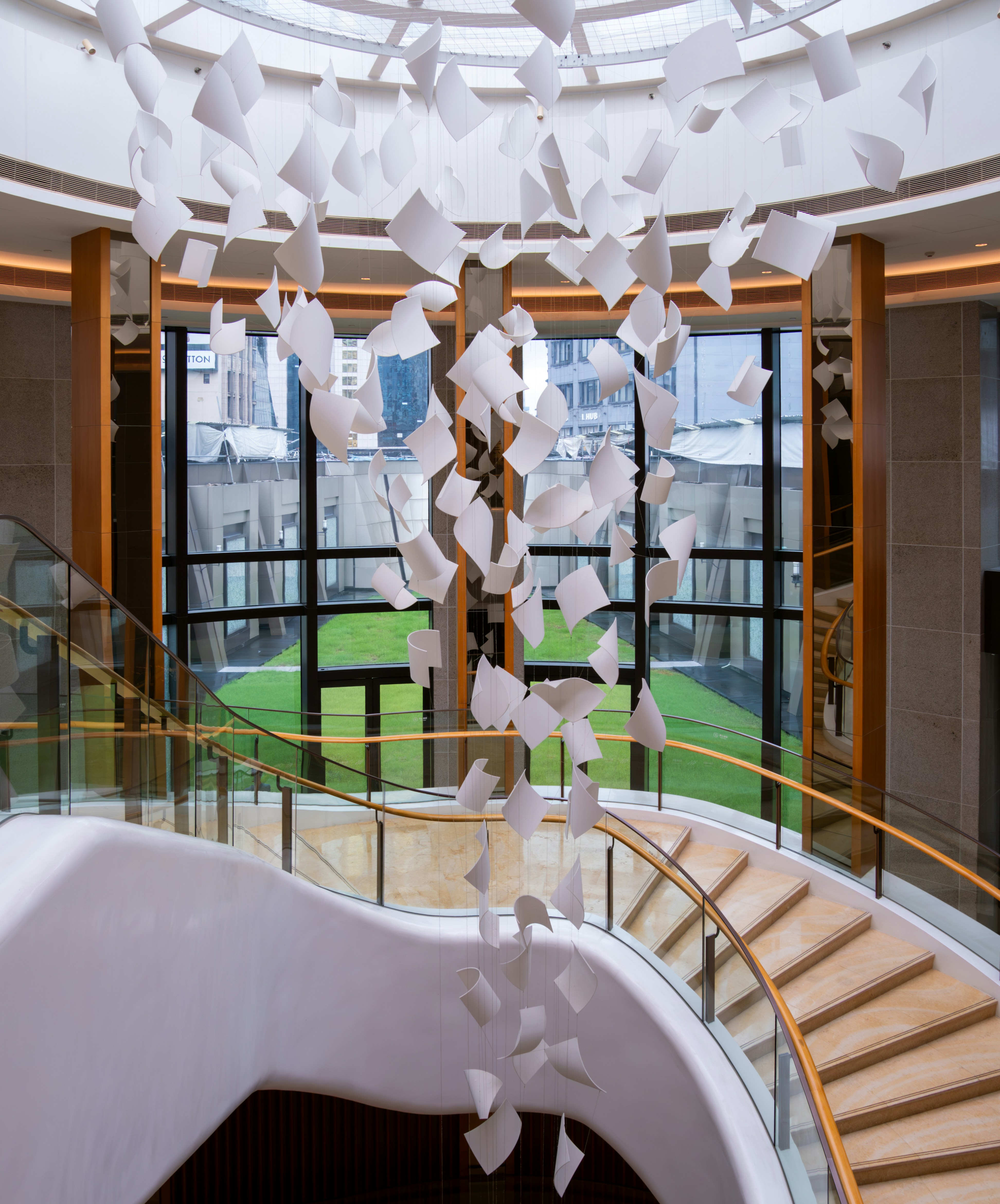 Paper Cascade Suspended Above a Curved Atrium Staircase