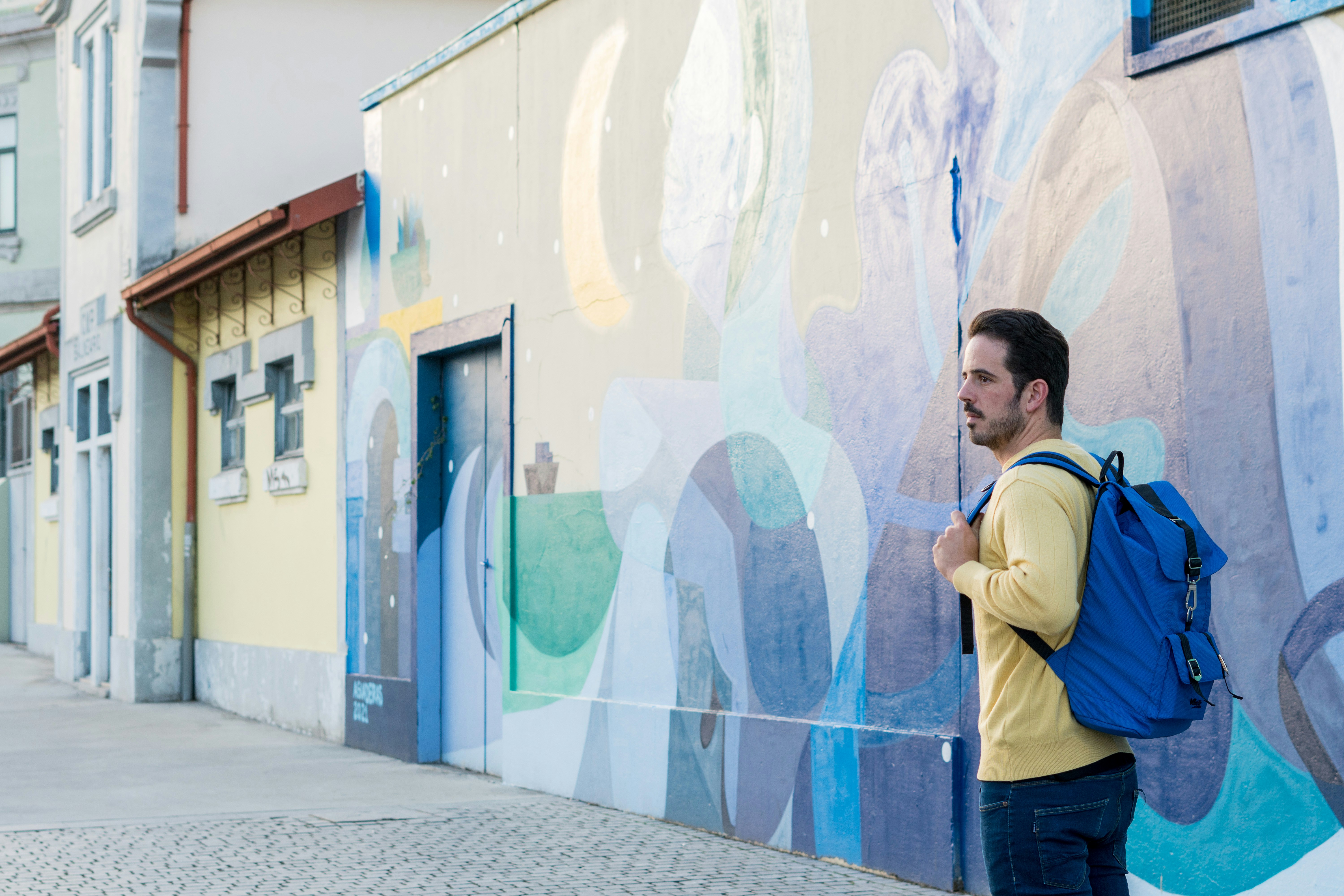 Backpack Portrait: A Quiet Moment Along a Wall of Abstract Color