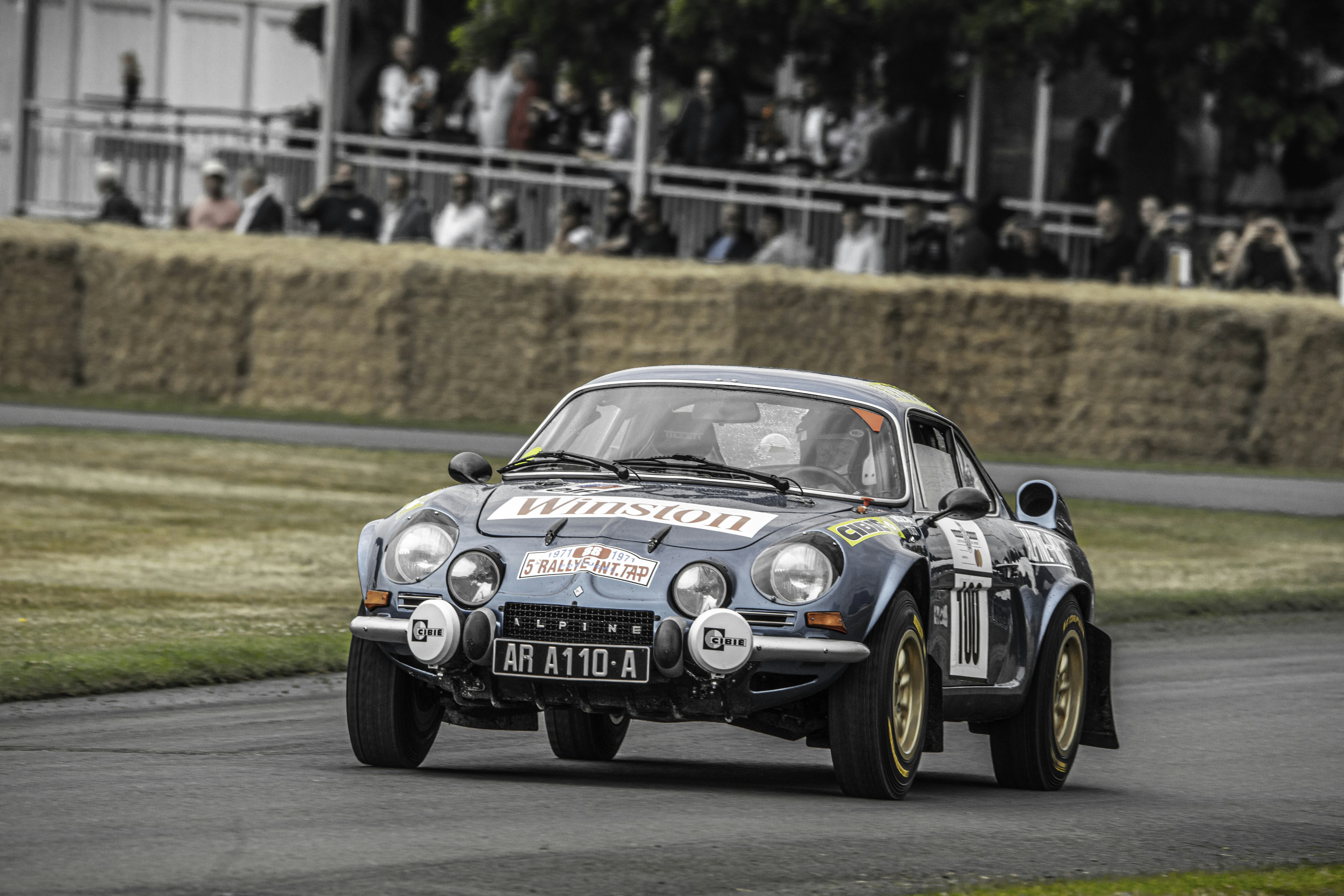 Rain-kissed Rally: Renault Alpine A110 grips a damp track as spectators watch