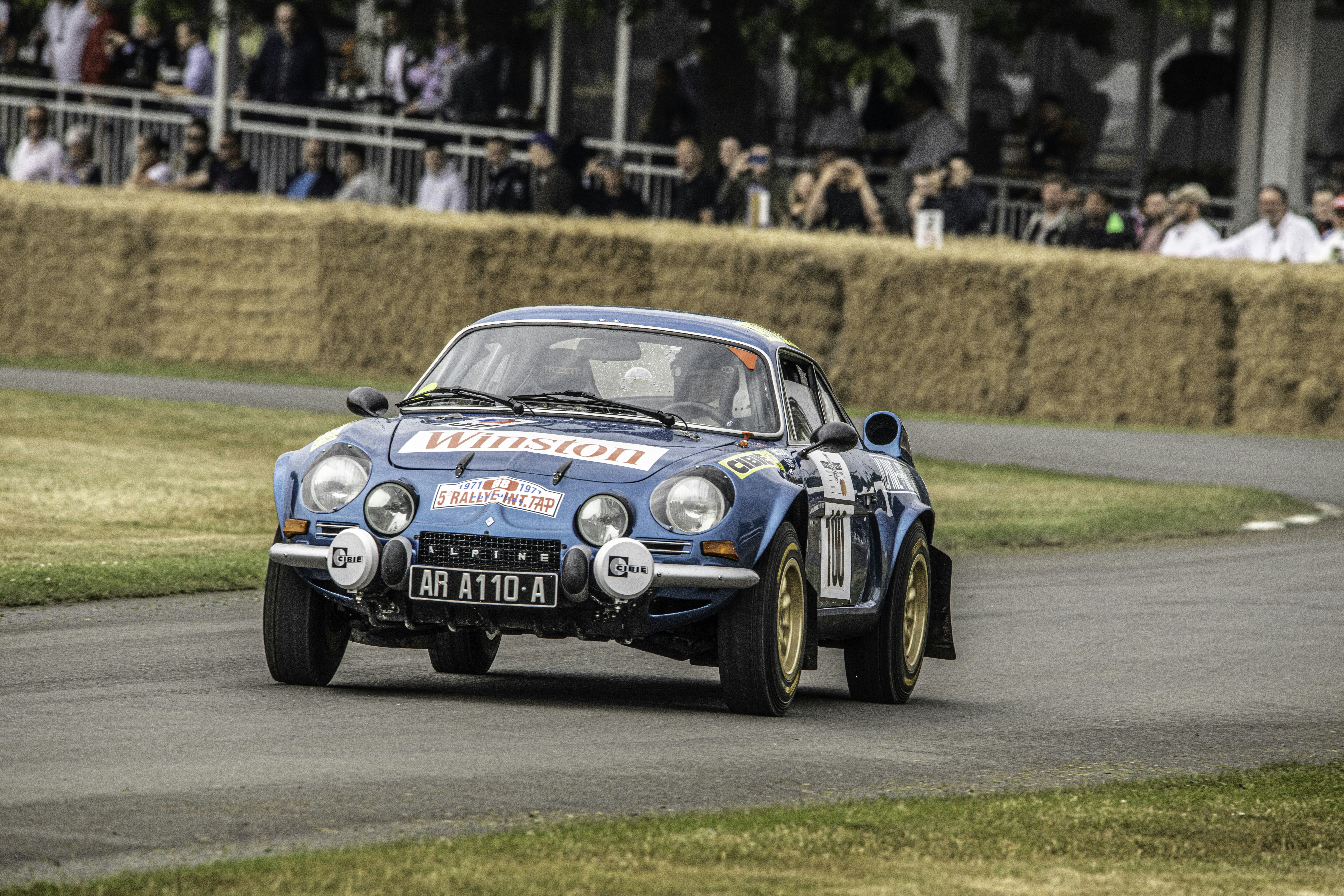 Blue Vintage Rally Car Bends Through a Parked-Audience Corner
