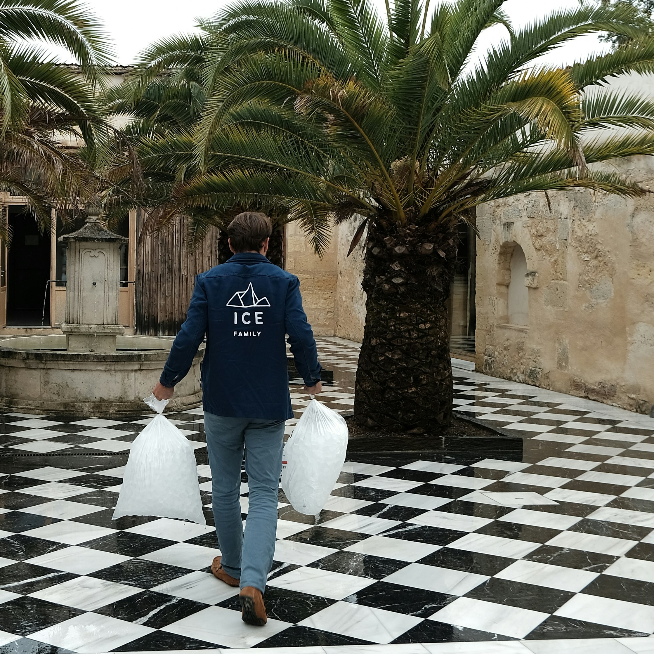 A man carrying two bags walking across a checkered floor photo – Free ...