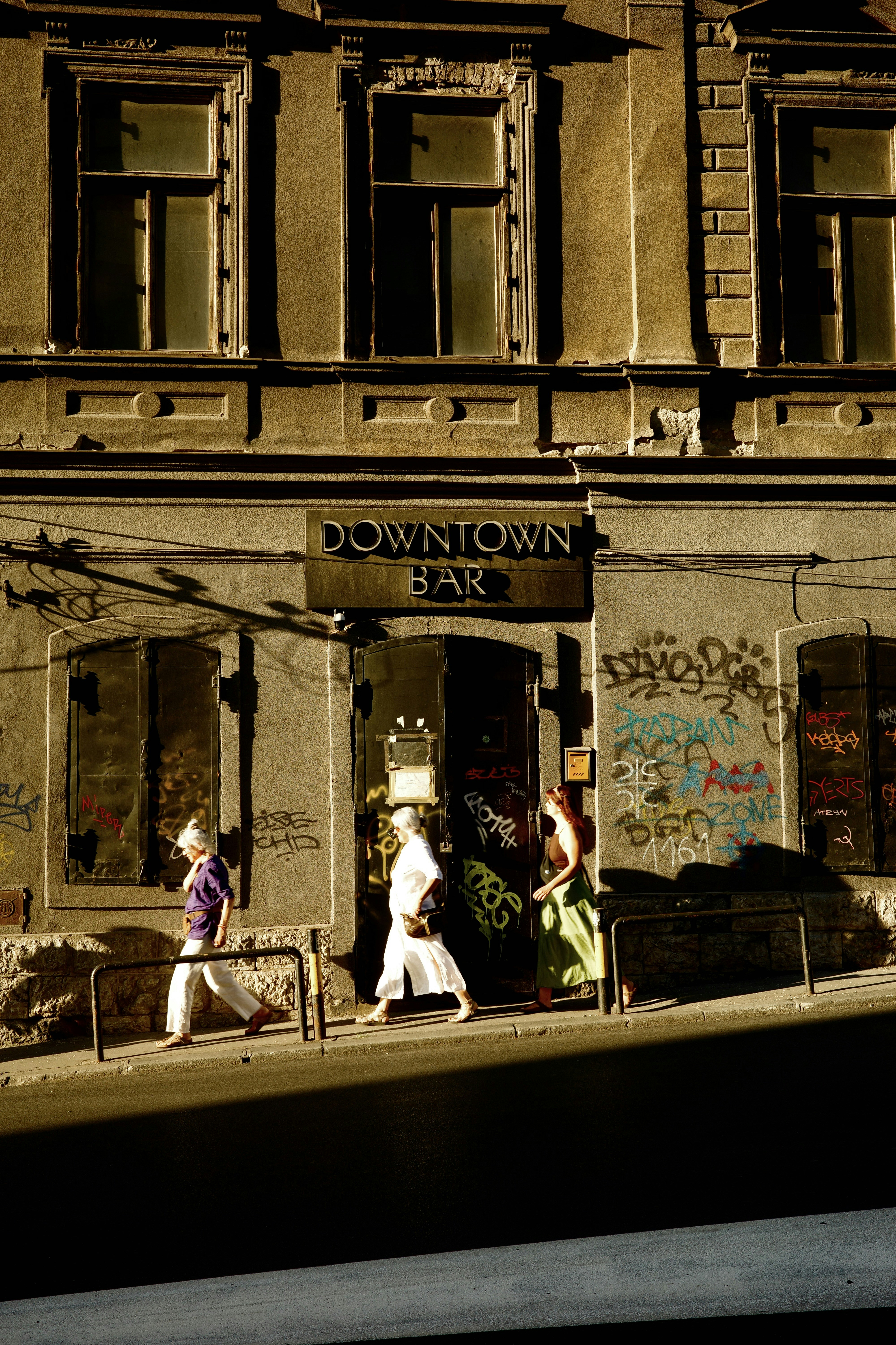 Golden Hour Stroll Past a Graffitied Downtown Bar