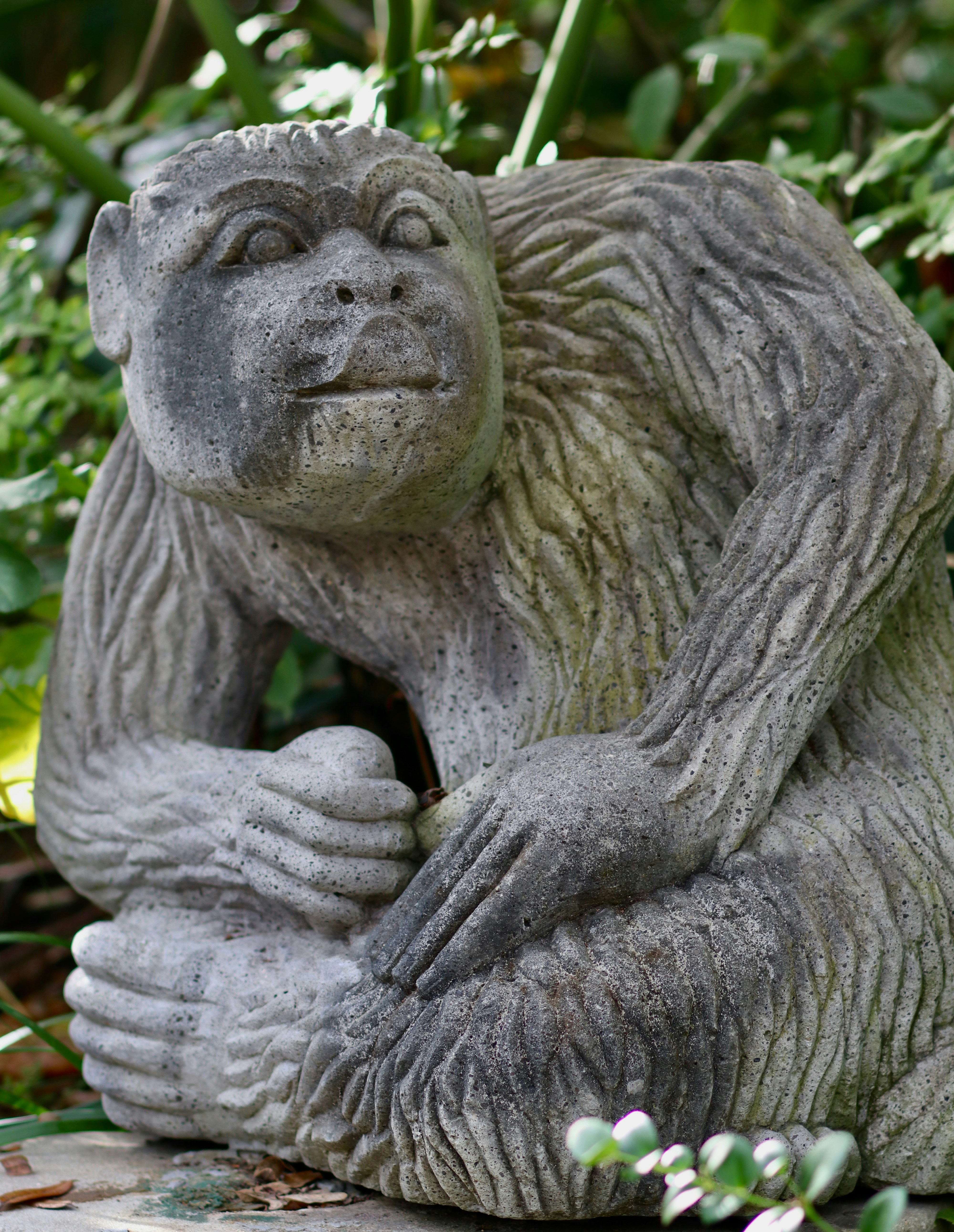 Garden Sentinel: Weathered Stone Monkey in Quiet Foliage