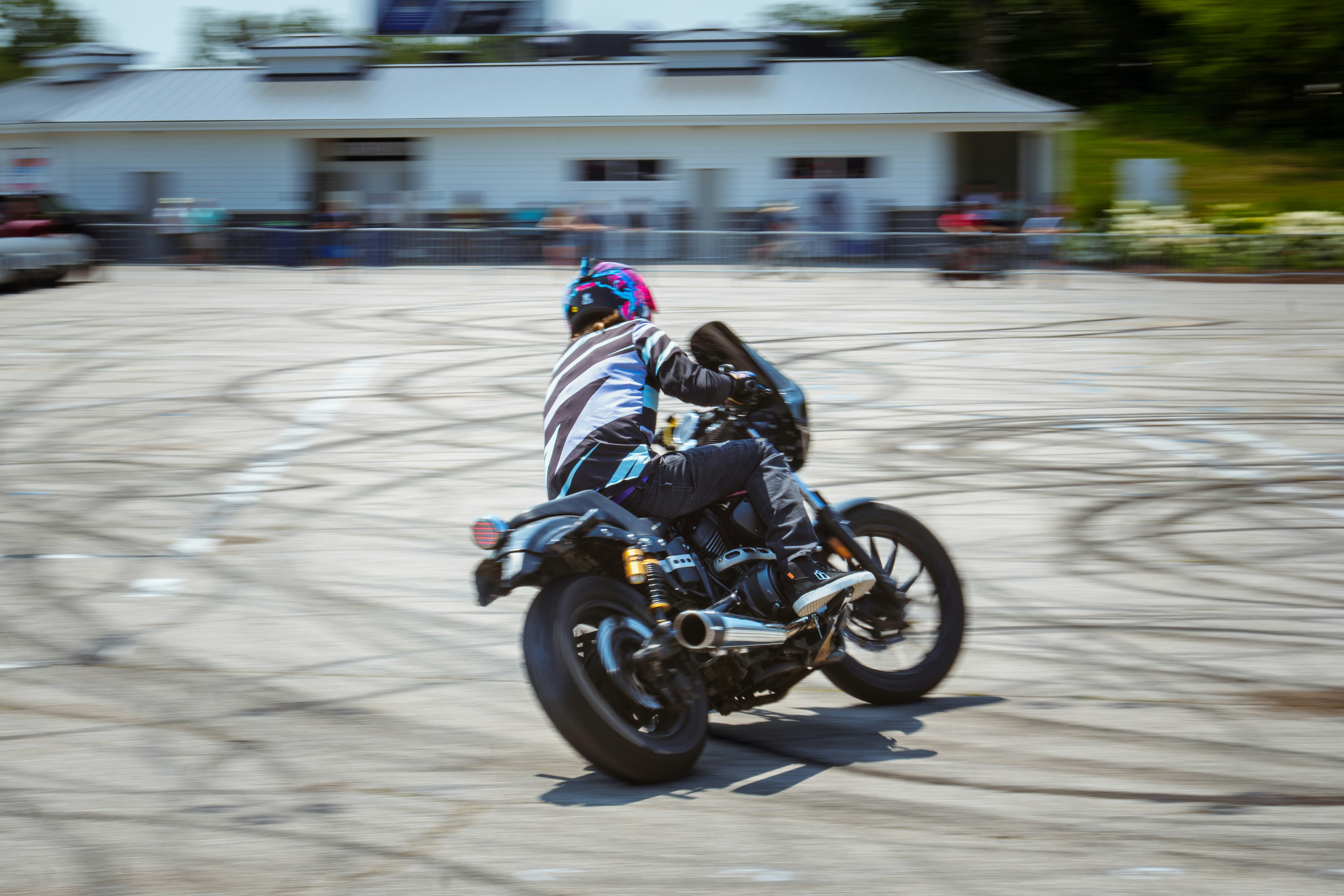 Motorcyclist executing a dynamic turn on asphalt with visible tire marks.
