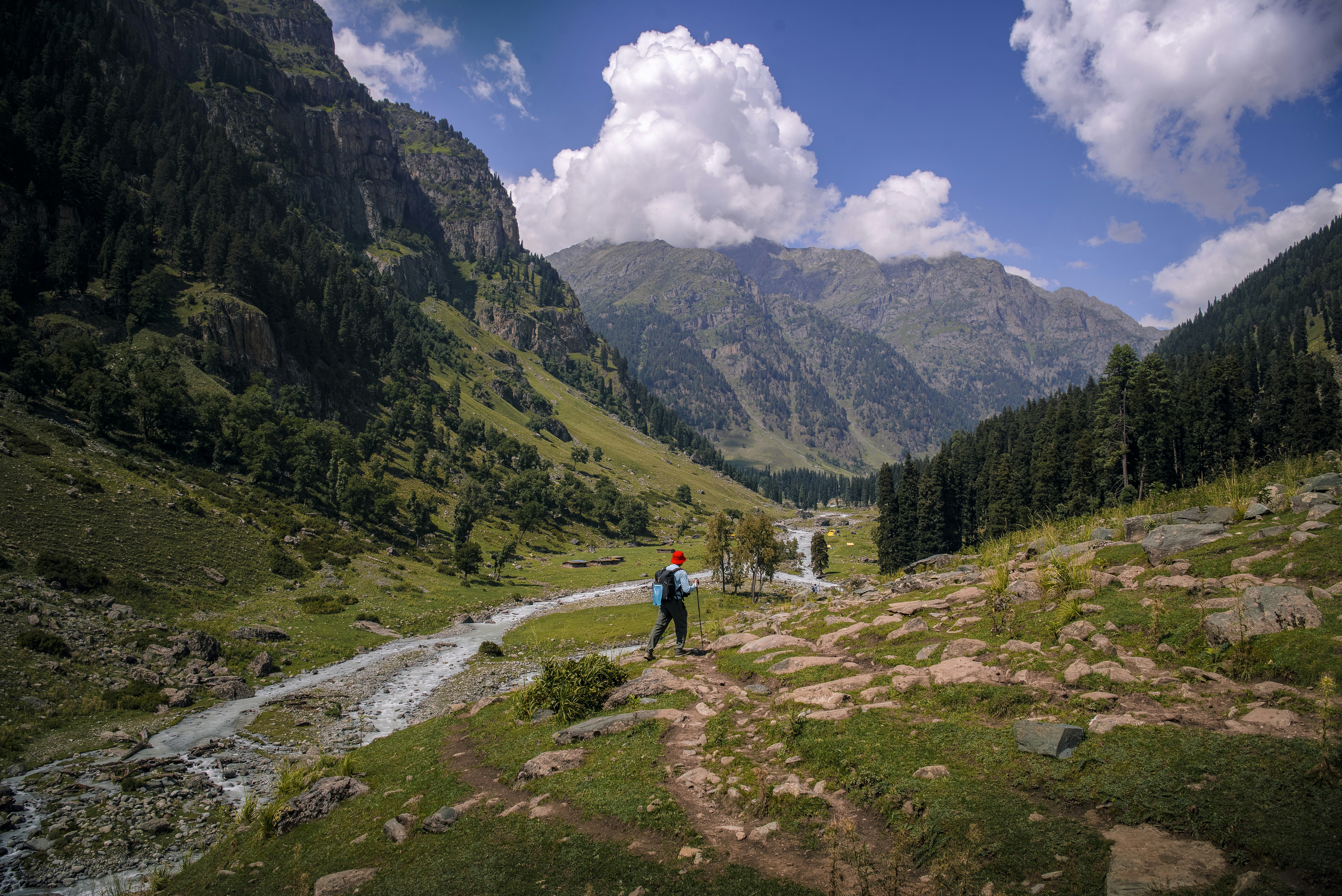 A man standing in a valley with mountains in the background