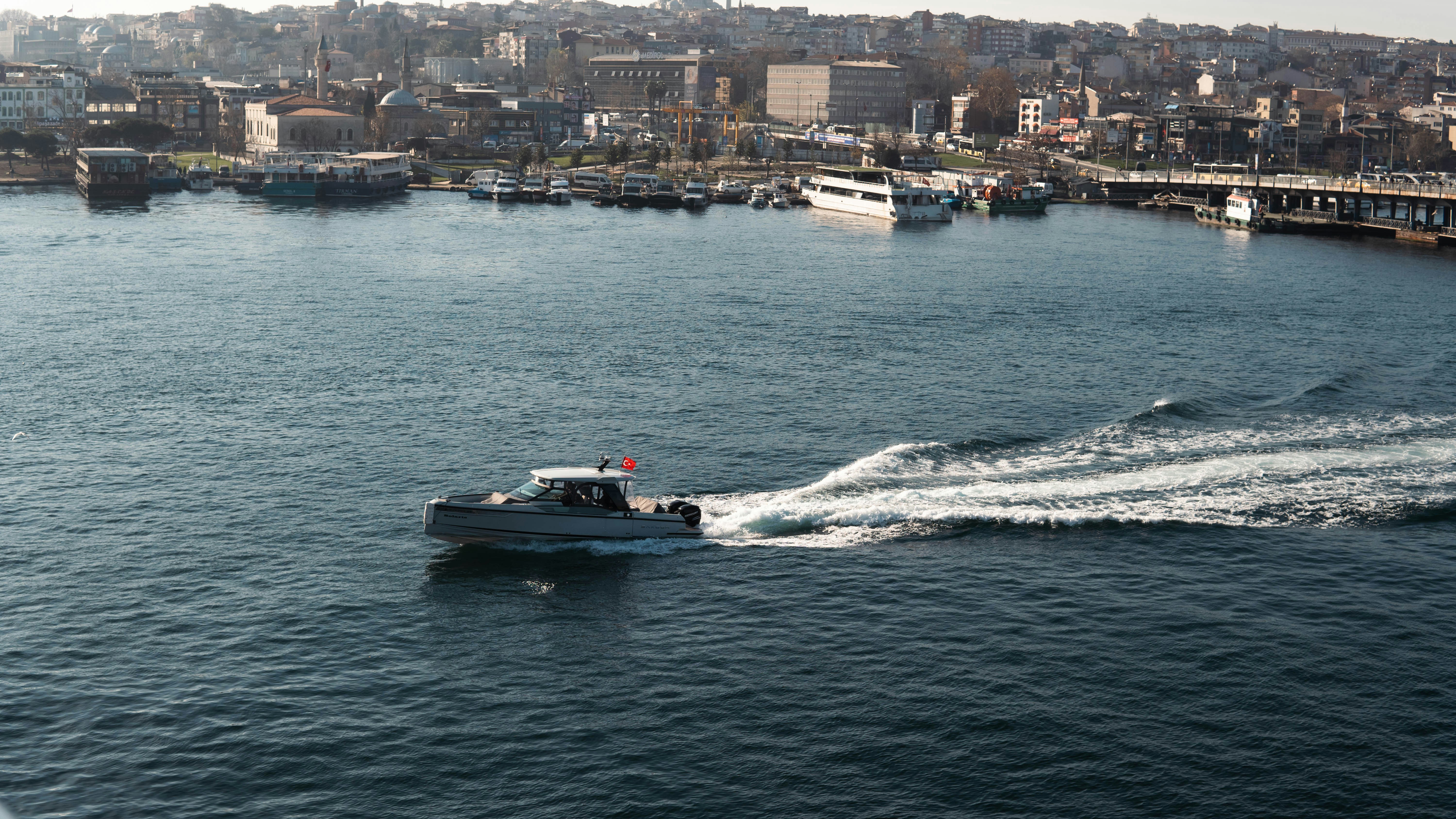 Wake in the Waterfront: a speeding speedboat slices a blue harbor with a city skyline