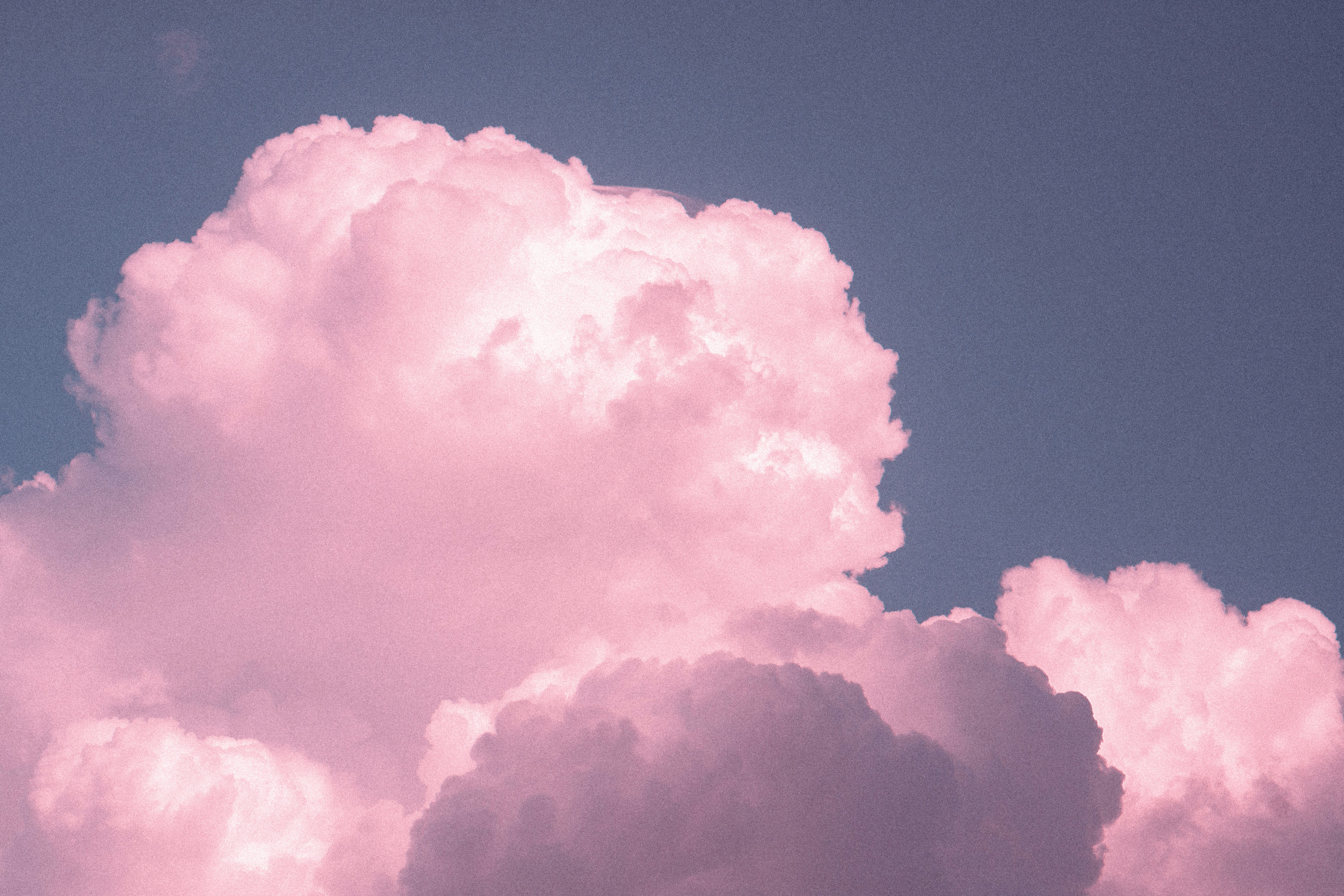 Soft pink clouds billowing against a serene blue backdrop, evoking a dreamy atmosphere. The delicate interplay of light creates a whimsical scene.