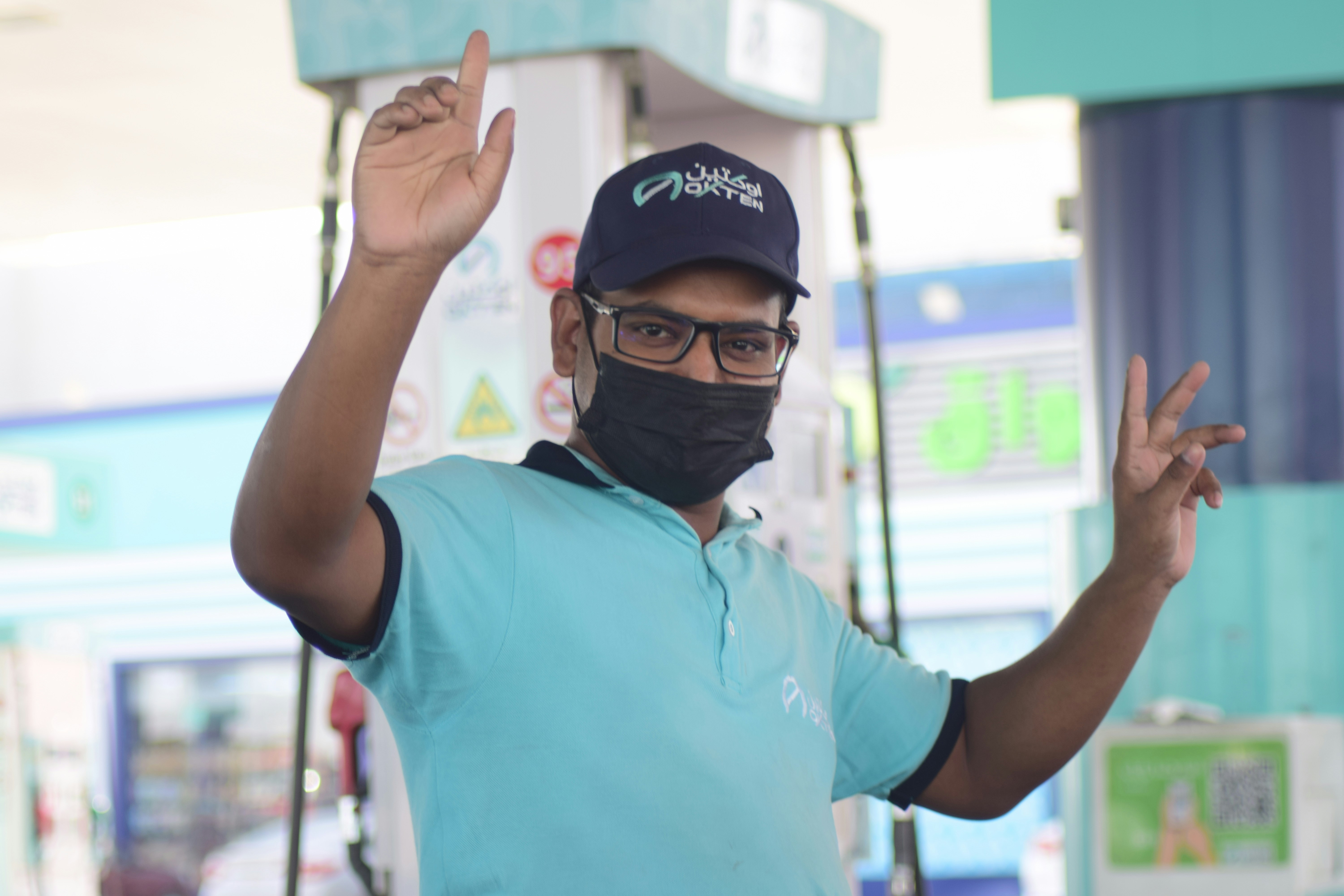 Masked Host at the Gas Station: Friendly Gesture Under a Bright Canopy
