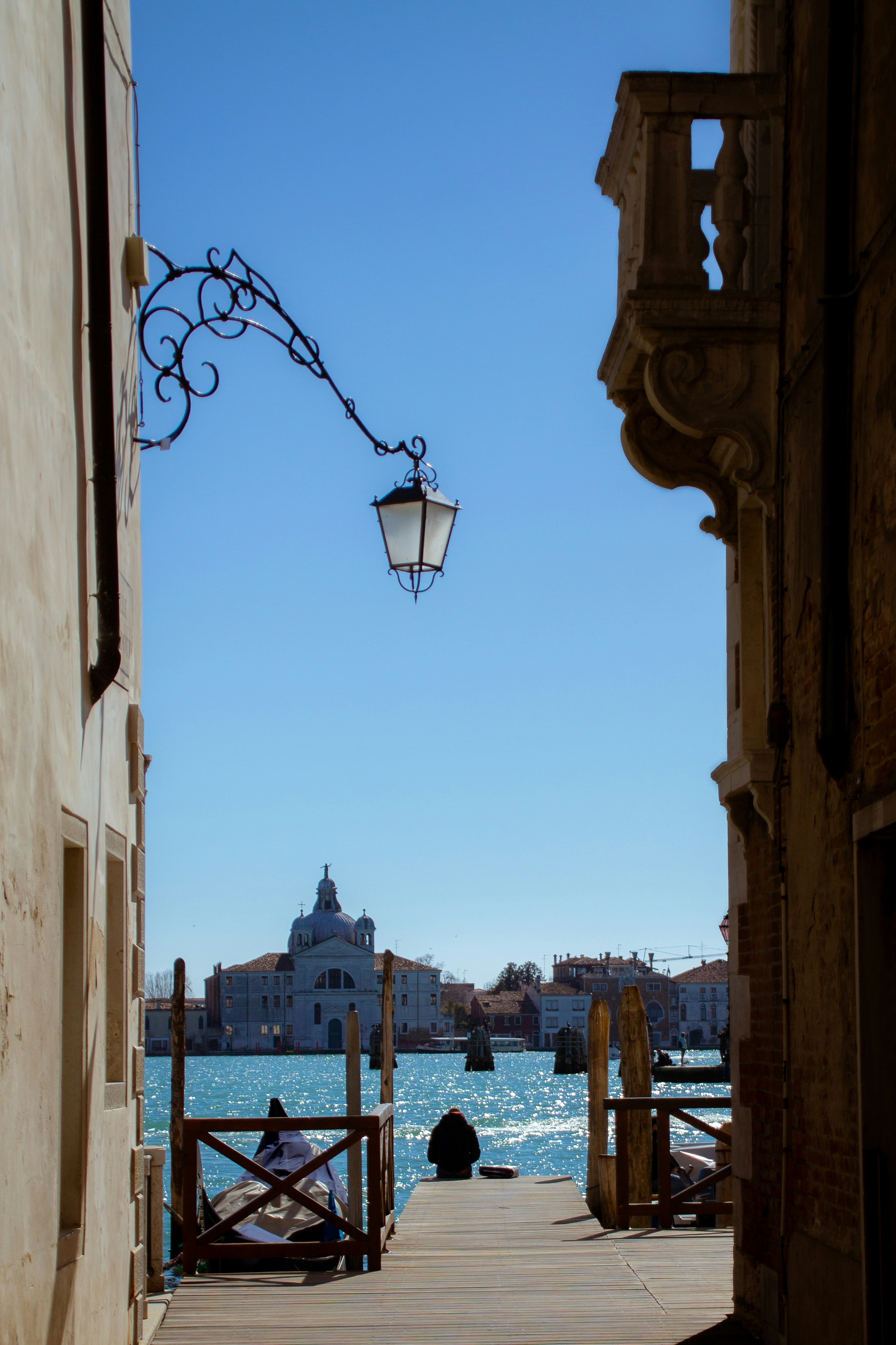 Lantern-Framed Corridor Toward a Sunlit Venetian Canal