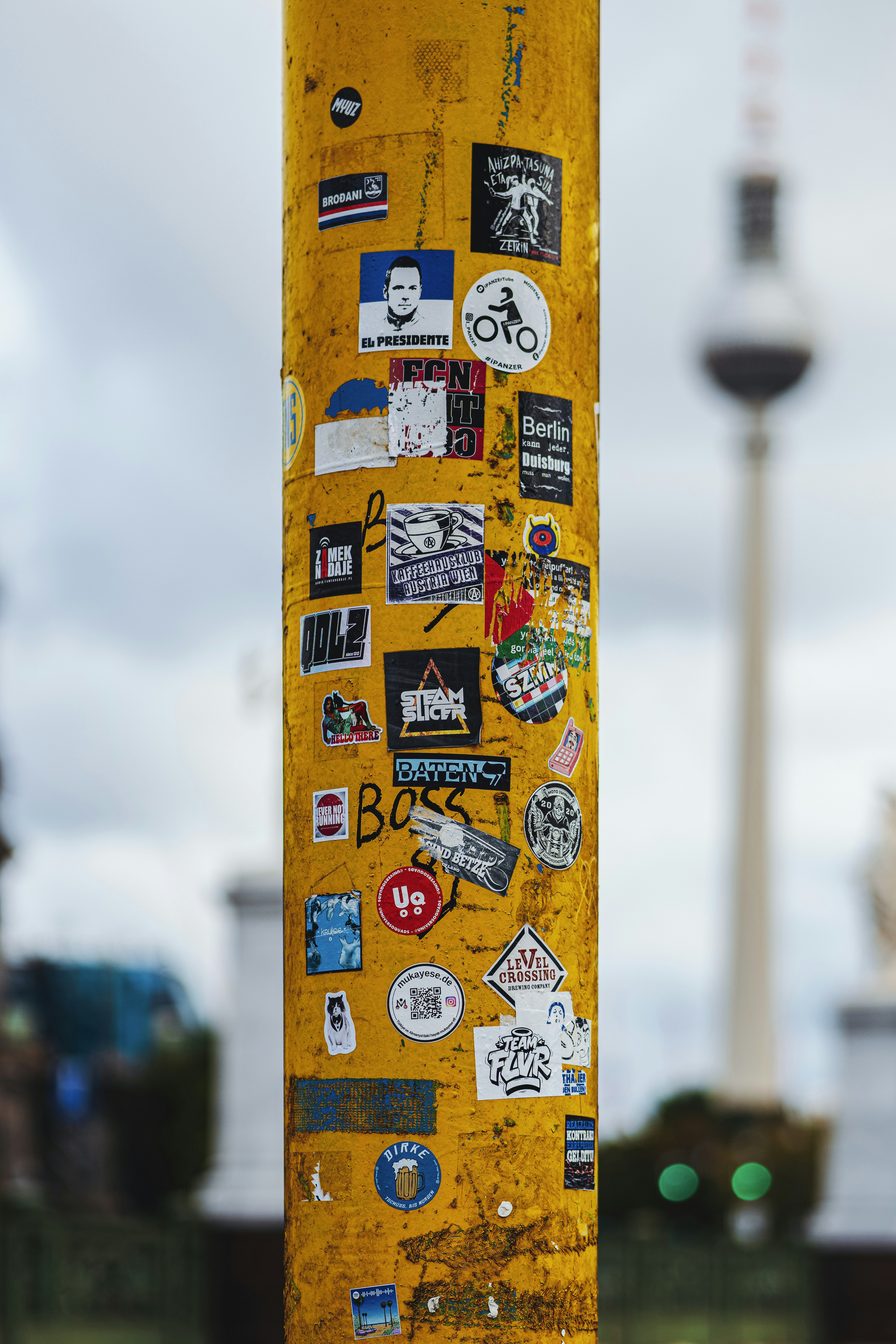A yellow pole with a bunch of stickers on it photo – Free Building ...