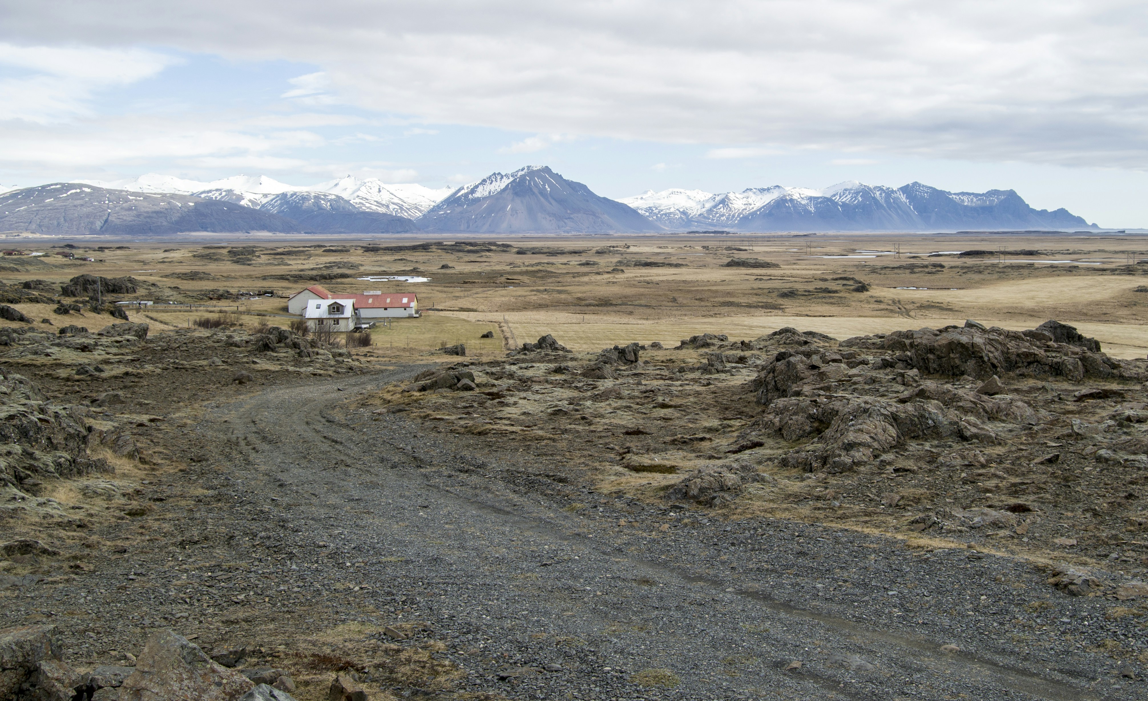 Isolated White House on Icelandic Plain Beneath Snowy Peaks