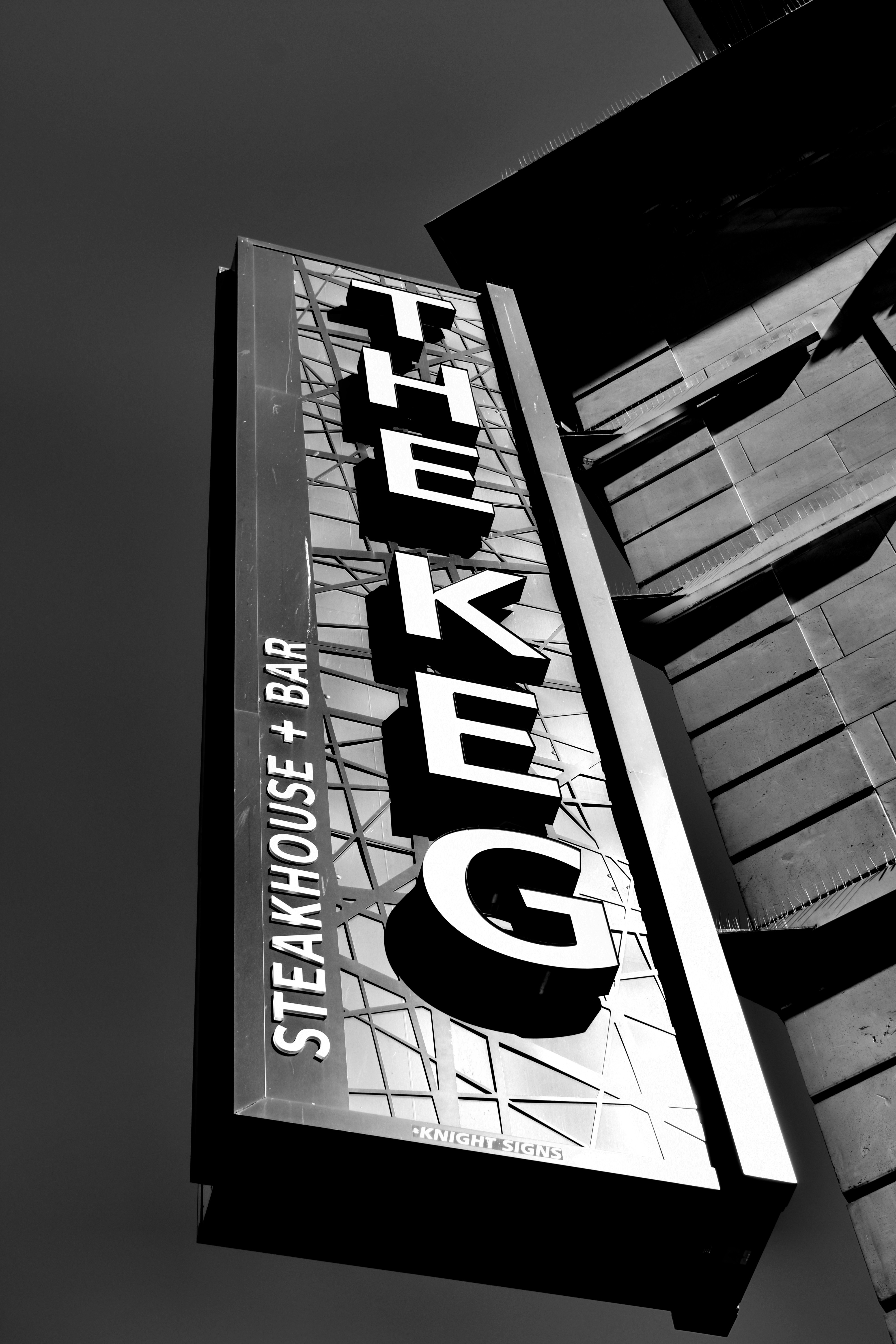 Monochrome Vertical STEAKHOUSE Sign: Stark Geometry Against the Sky