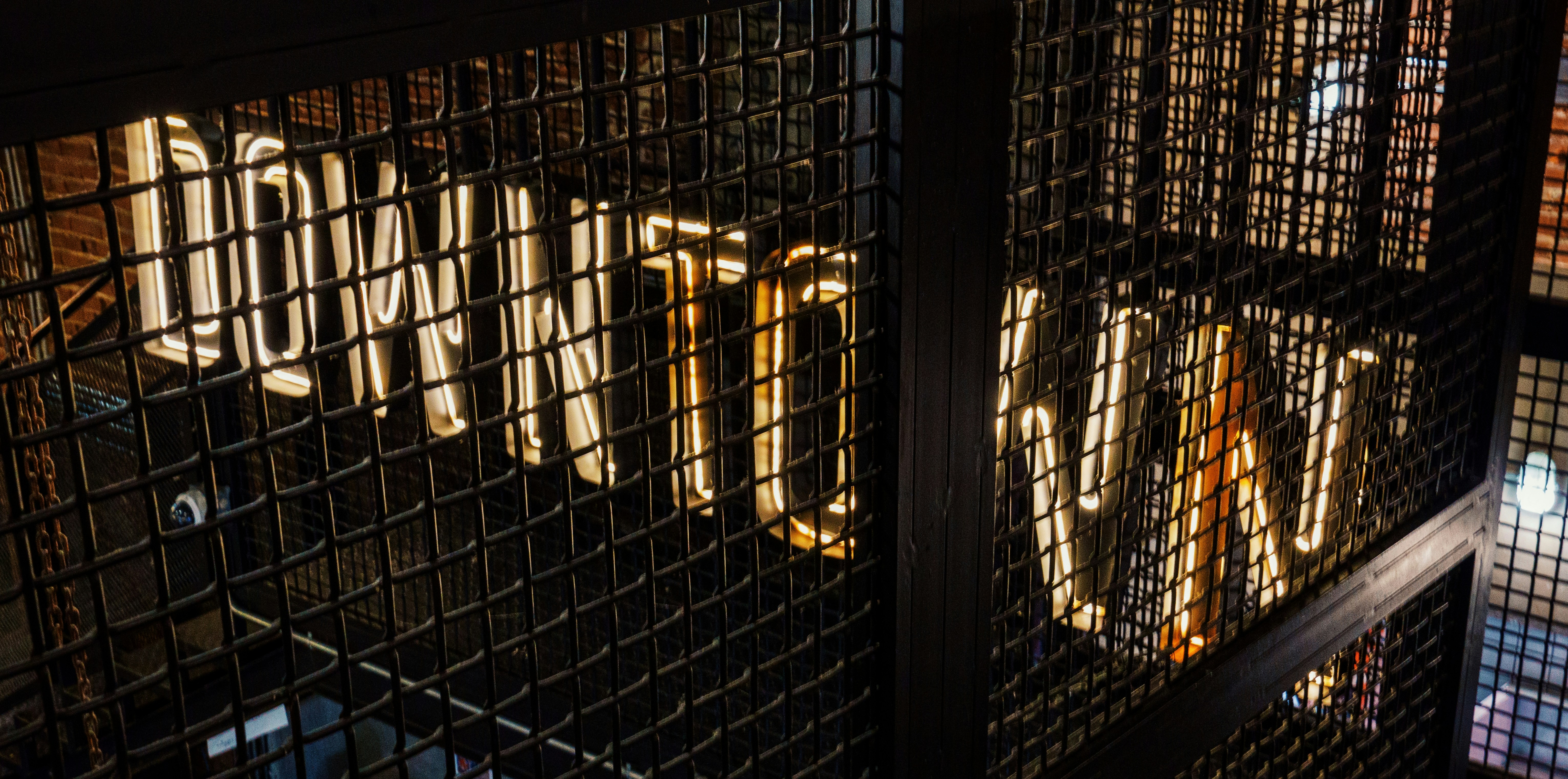 Neon Script Behind Steel Mesh: Night Geometry Through Grating
