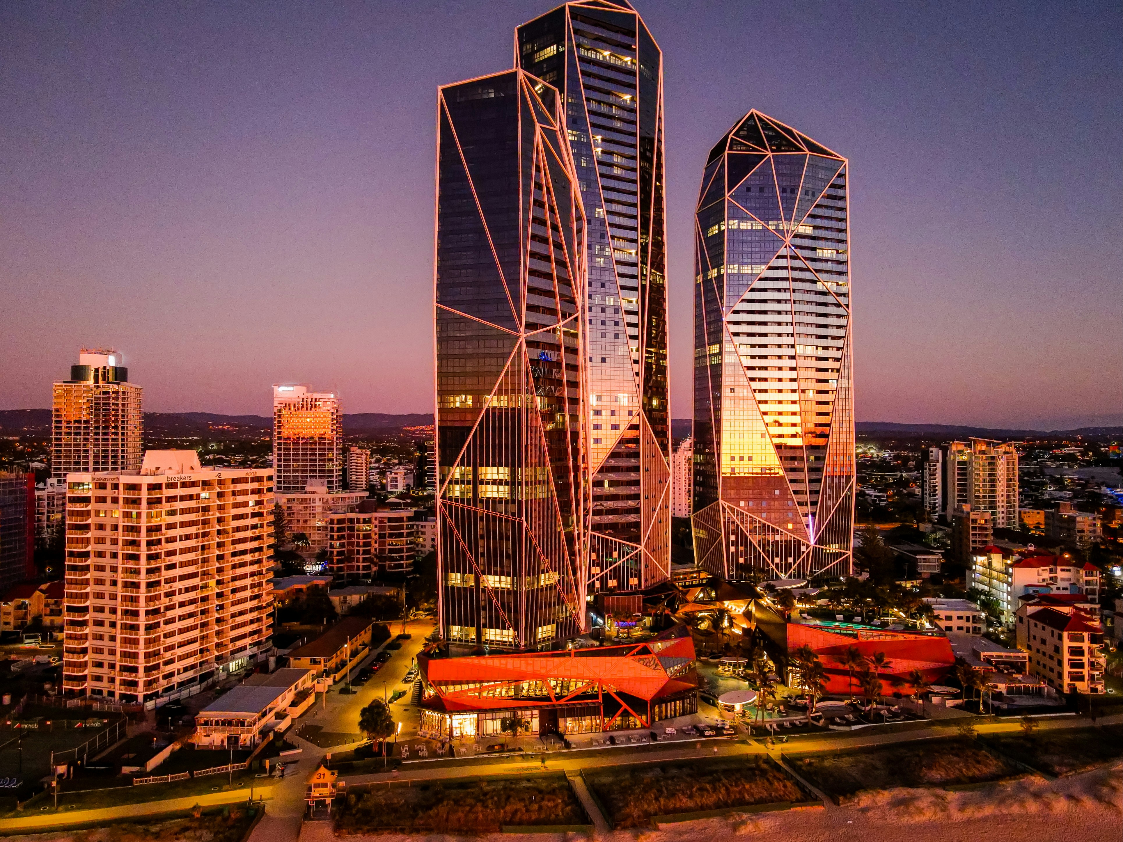 City skyline at dusk with skyscrapers reflecting sunset hues in the glass facades.