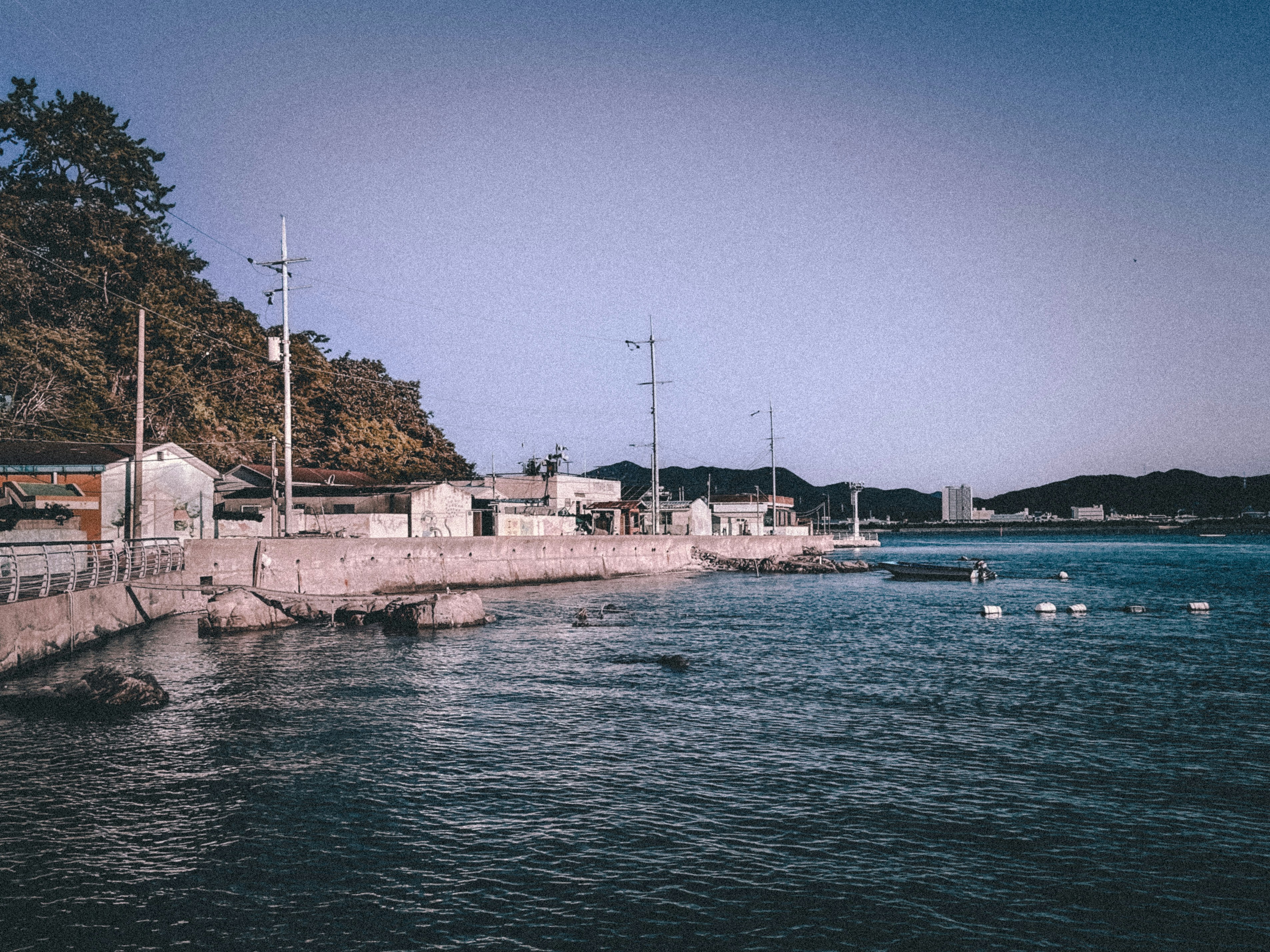 Quiet Harbor Line: Boats, Concrete Docks, and Distant Hills