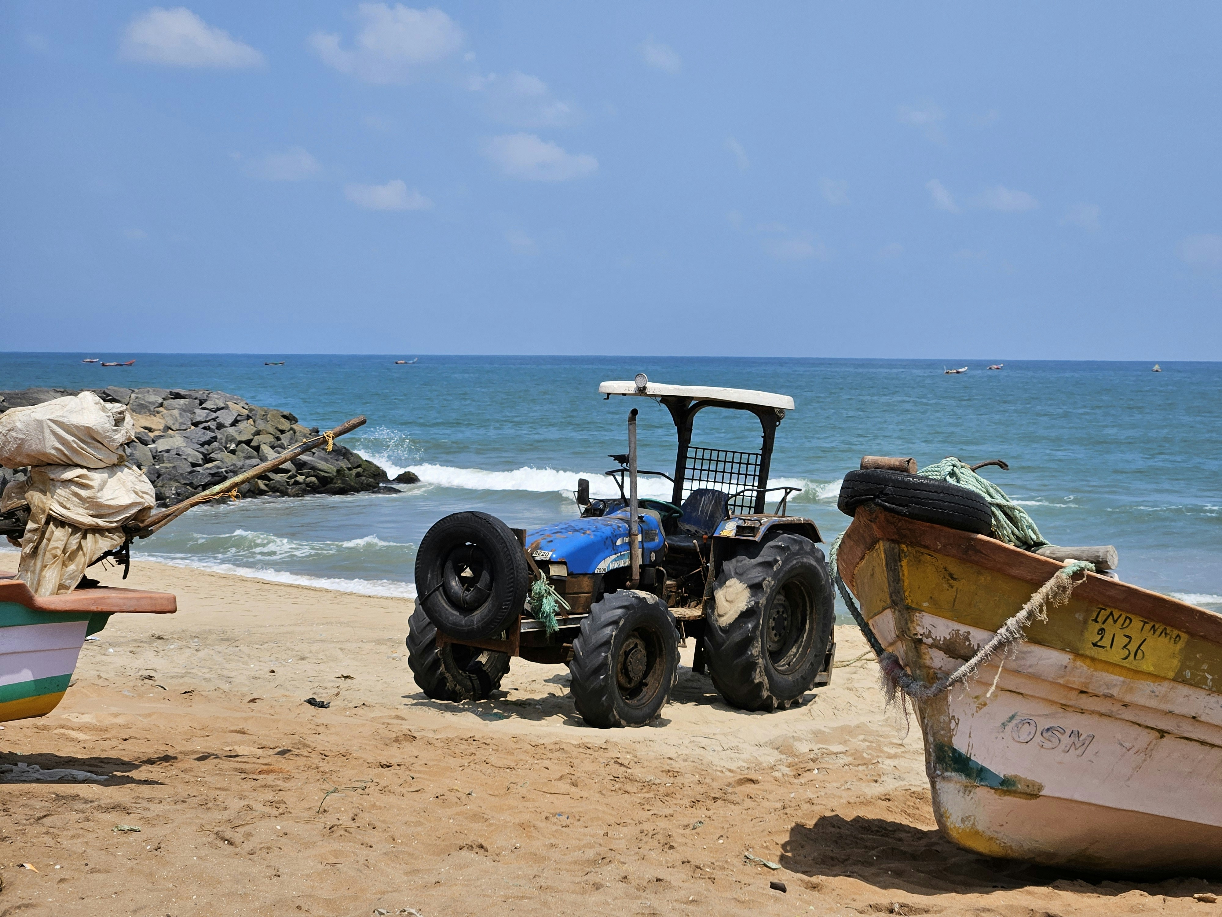 A tractor parked on the beach next to a boat photo – Free Auroville ...