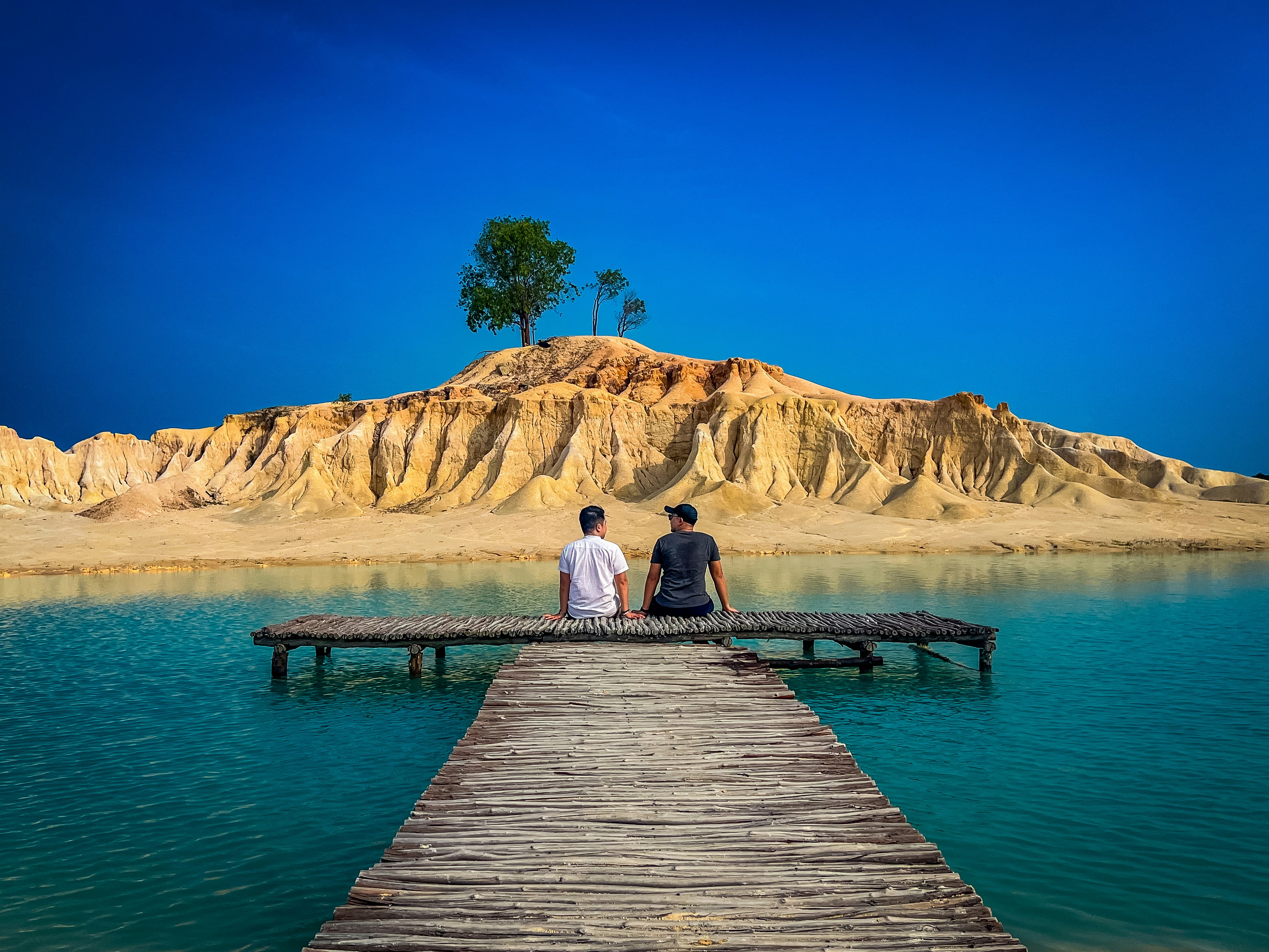 A couple of people sitting on a dock photo – Free Human Image on Unsplash