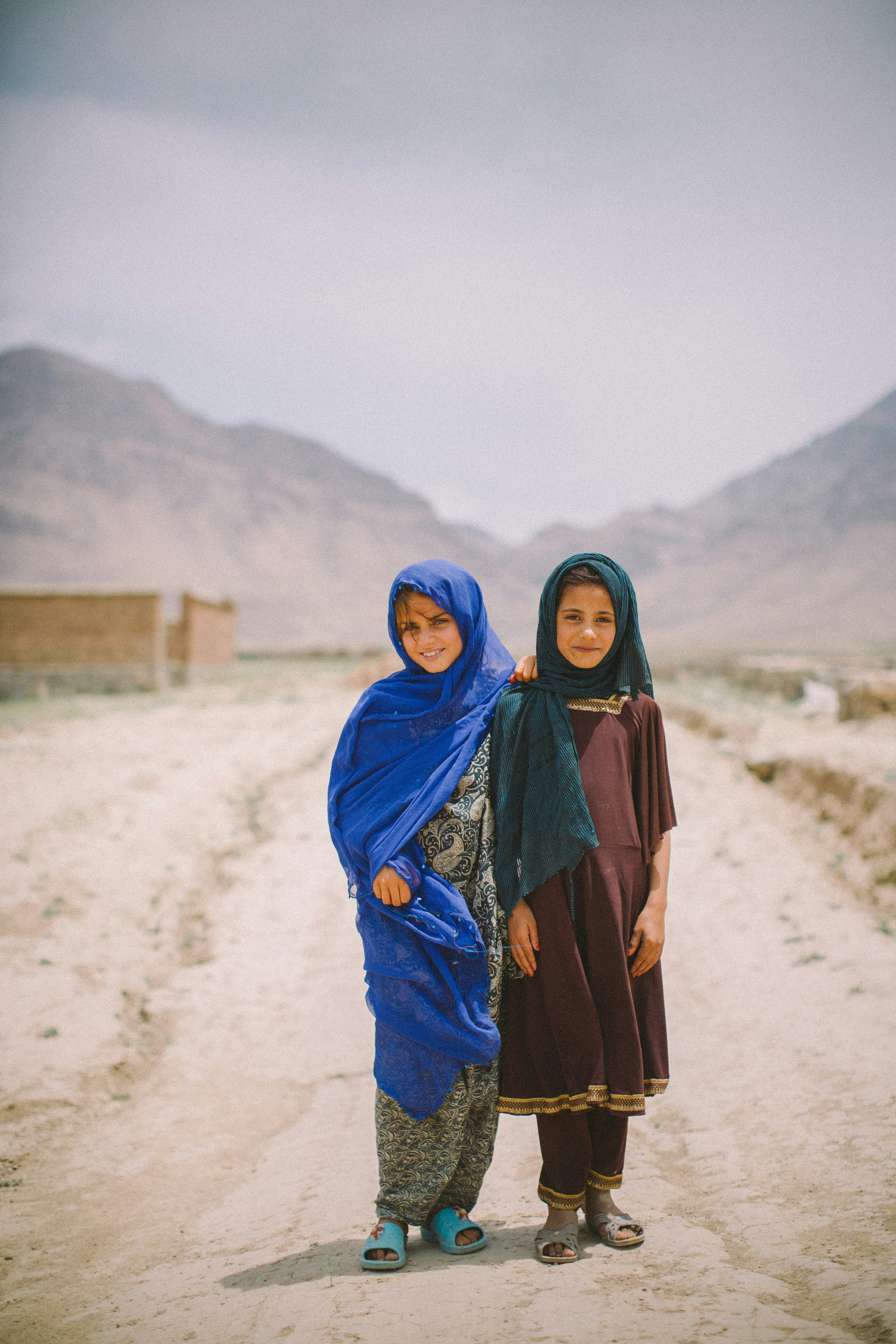 Afghan girls in village | Two women standing in the middle of a dirt road