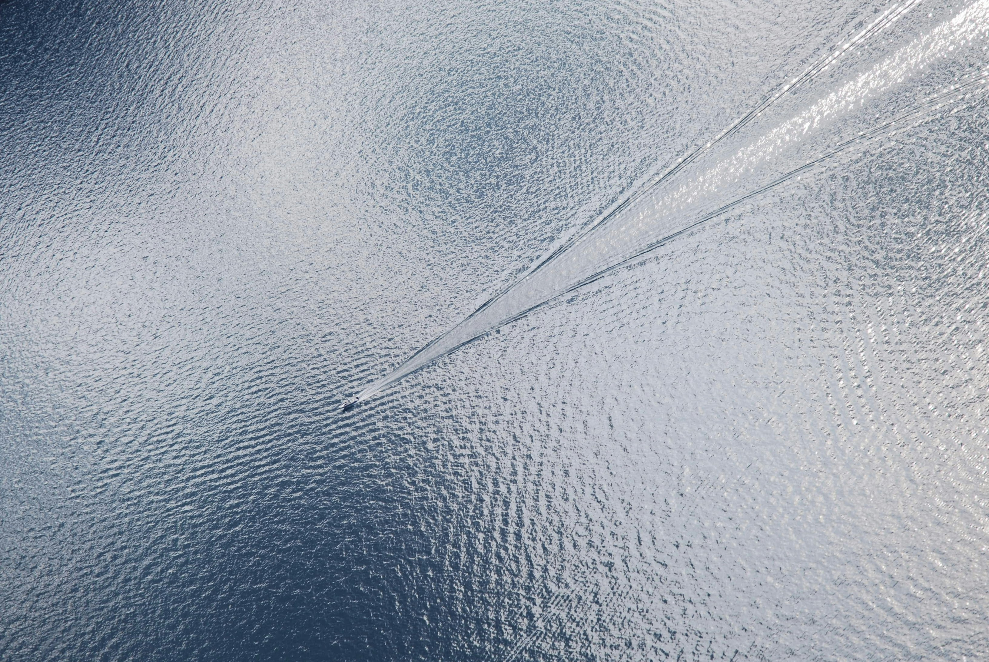 Diagonal Wake Across a Textured Blue Sea