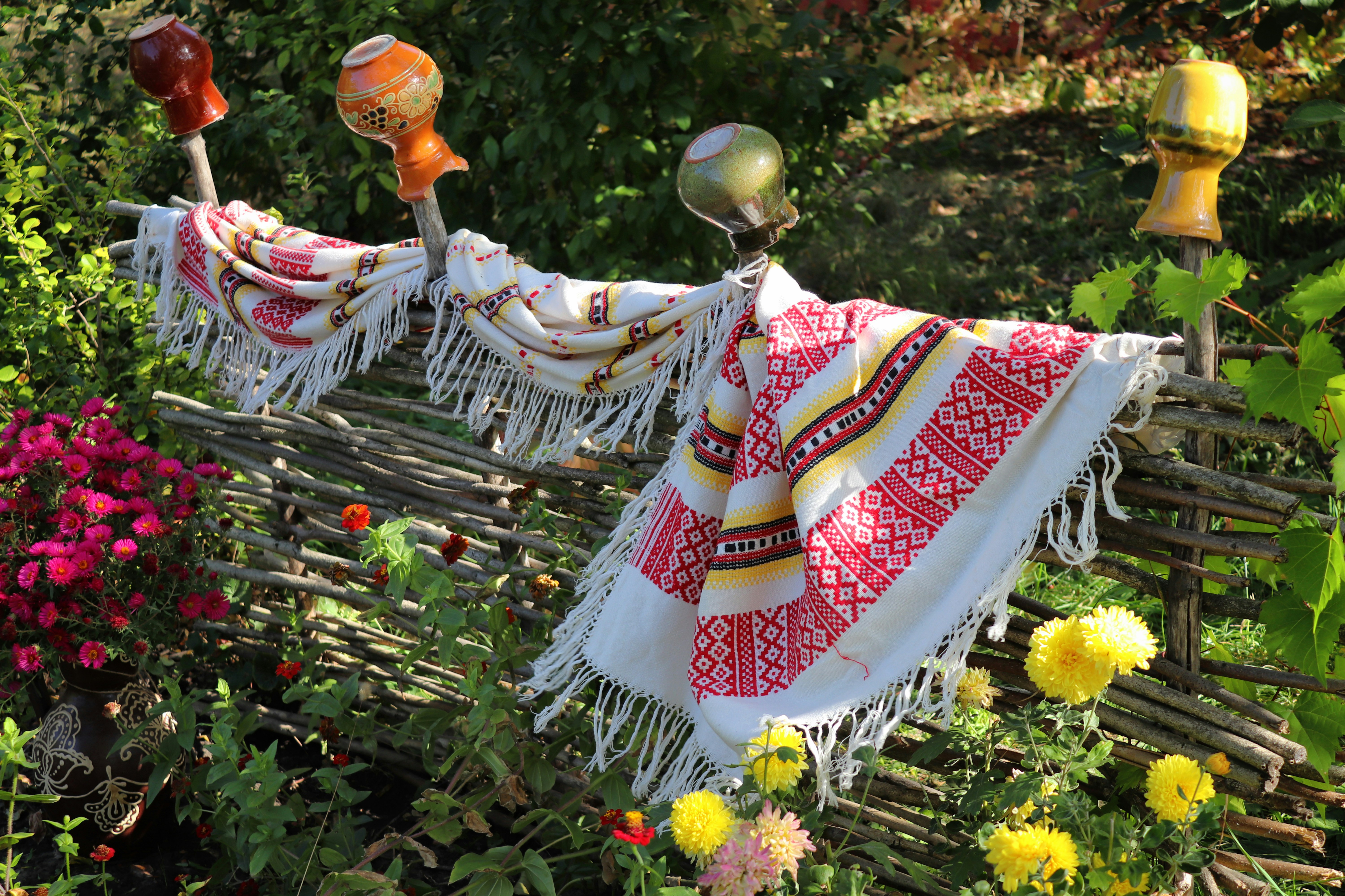 Fringed textile cascade over a rustic fence amid garden blooms