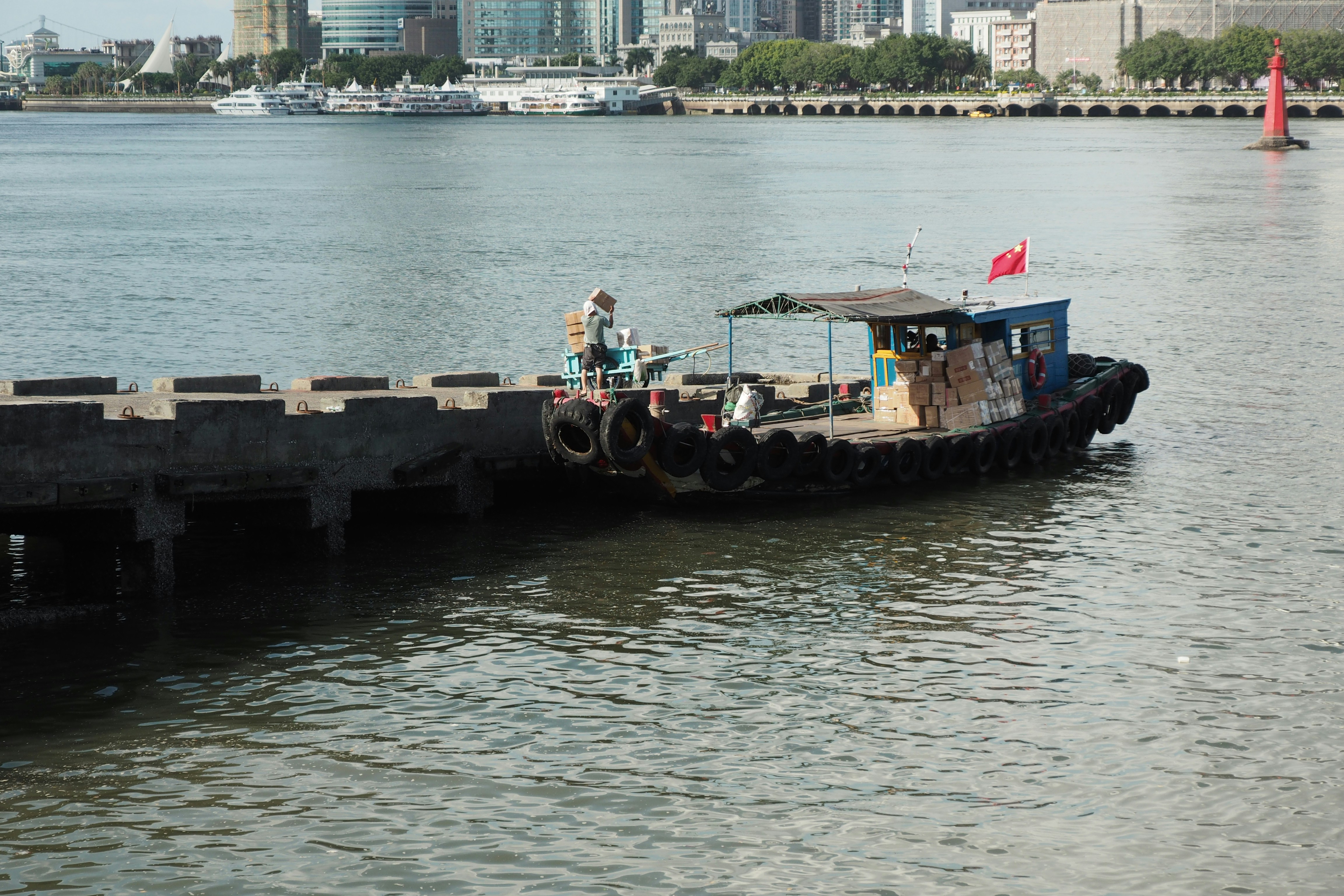 Crate-Laden Tugboat at a Quiet Harbor, with a City Skyline in the Distance
