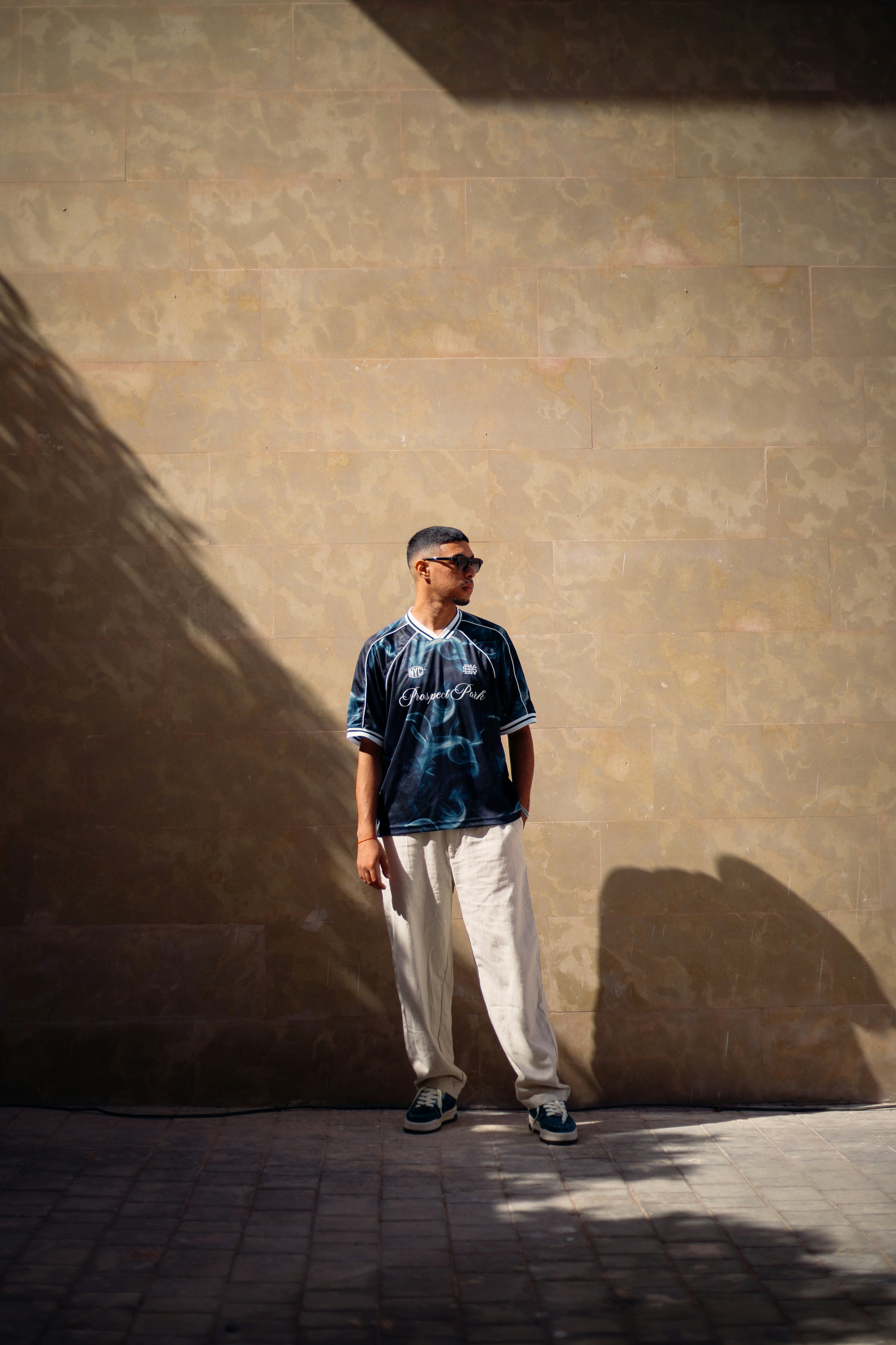 Sunlit Solitude: Casual Portrait Against a Textured Wall