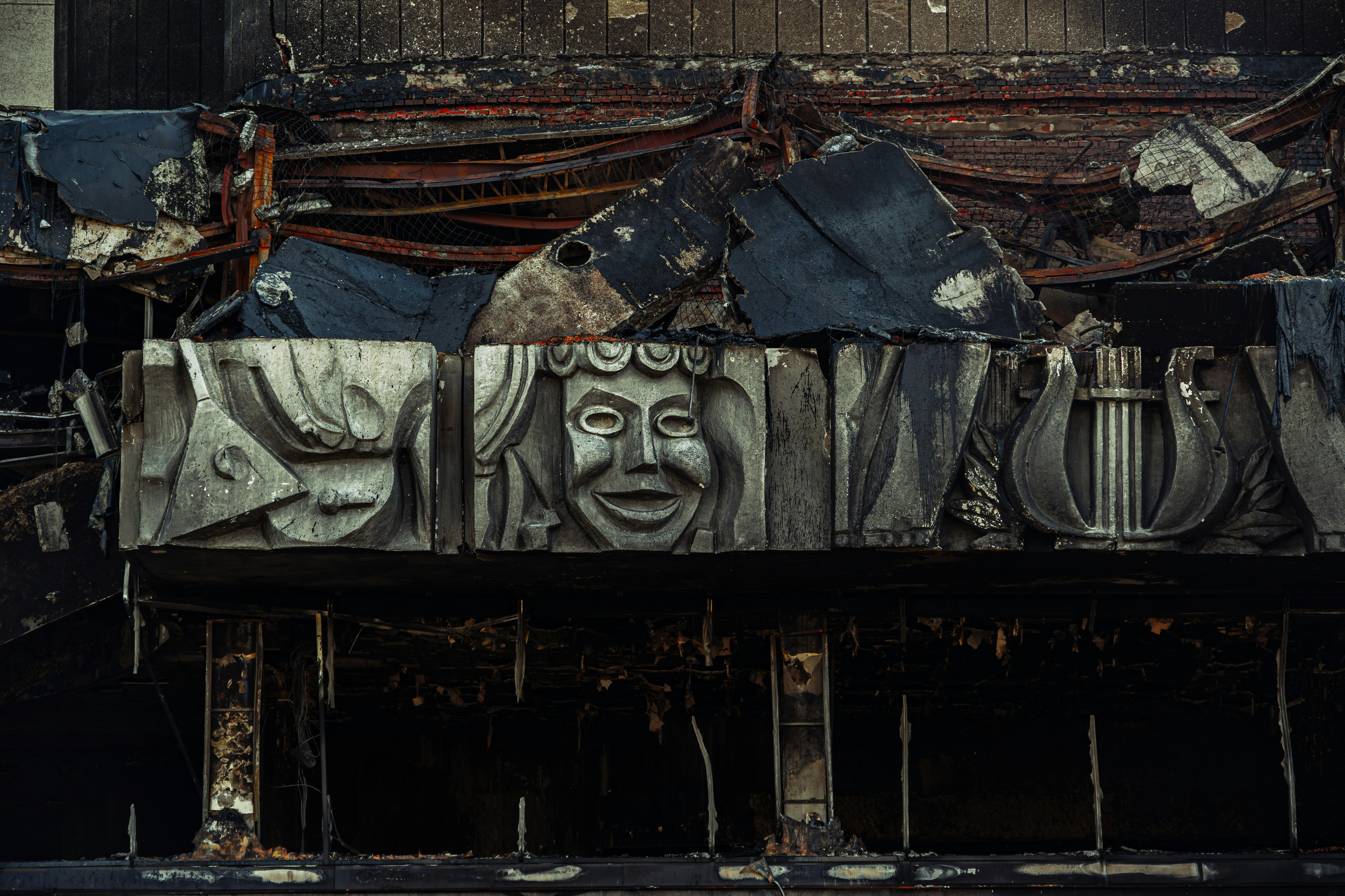 Intricate burnt relief carvings on a decaying building, showcasing artistic expressions now marred by time and fire.
