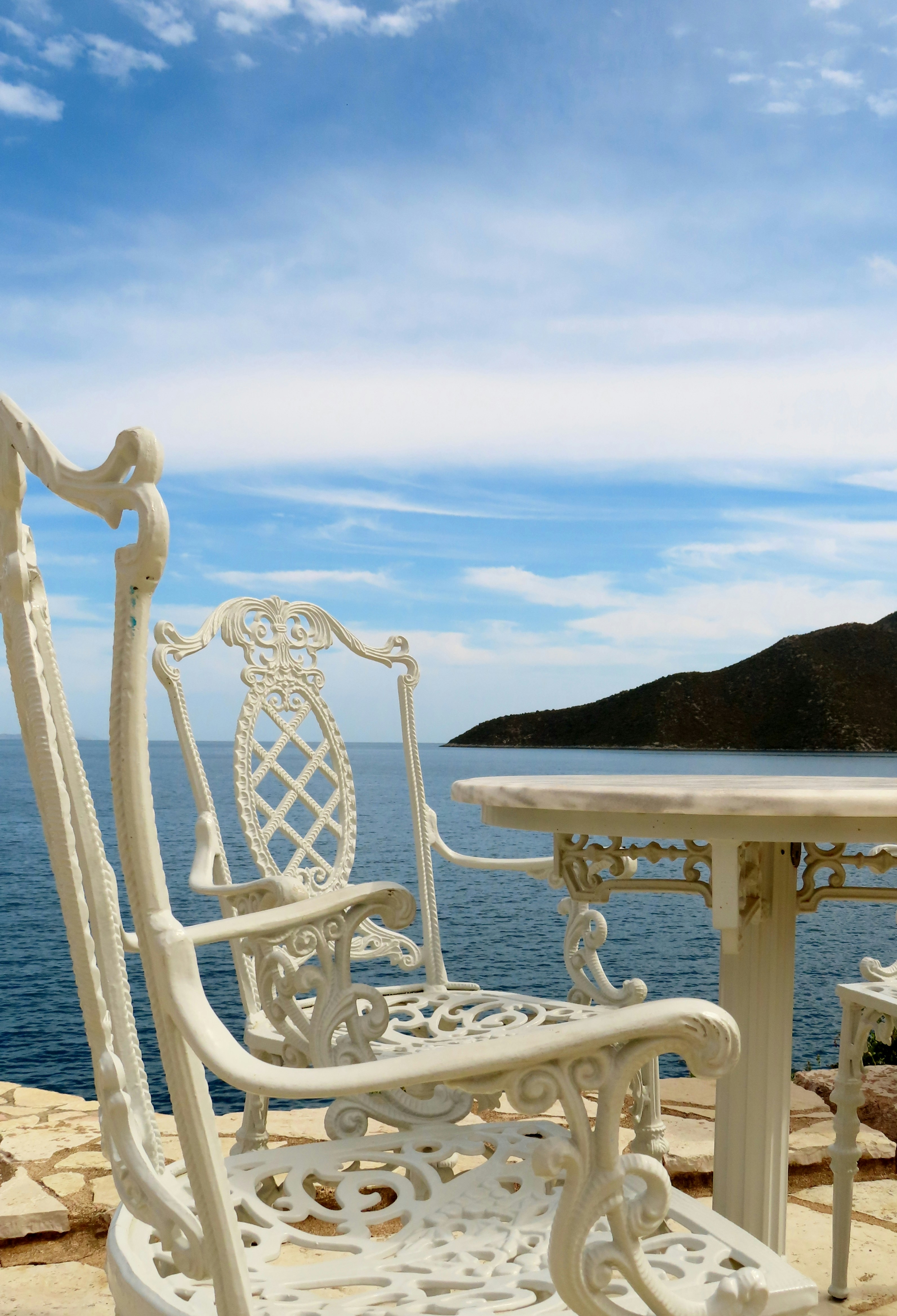 A white table and chair sitting on top of a cliff photo – Free Sea ...