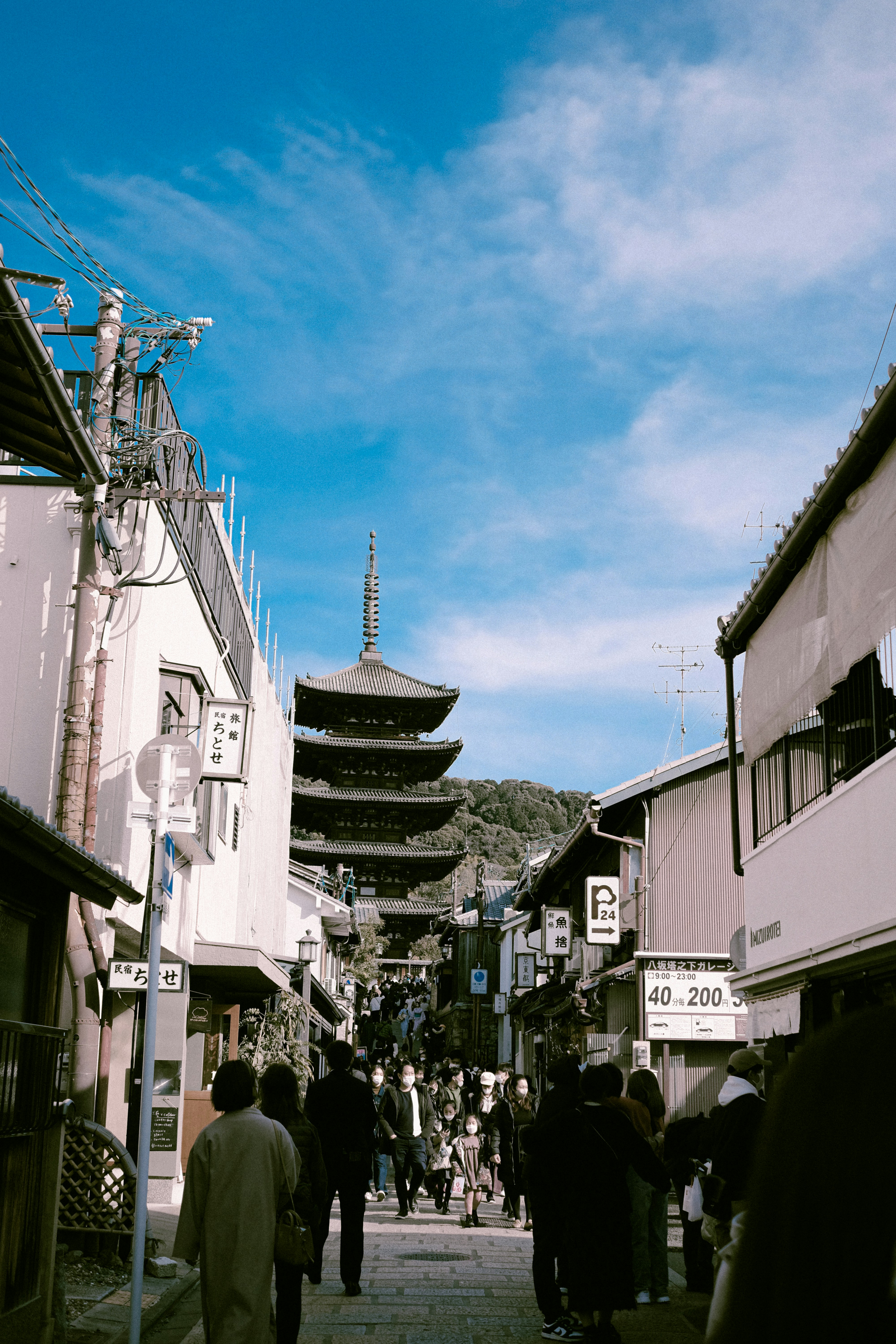 Towards the Pagoda: A Sunlit Kyoto Street Framed by Quiet Crowds