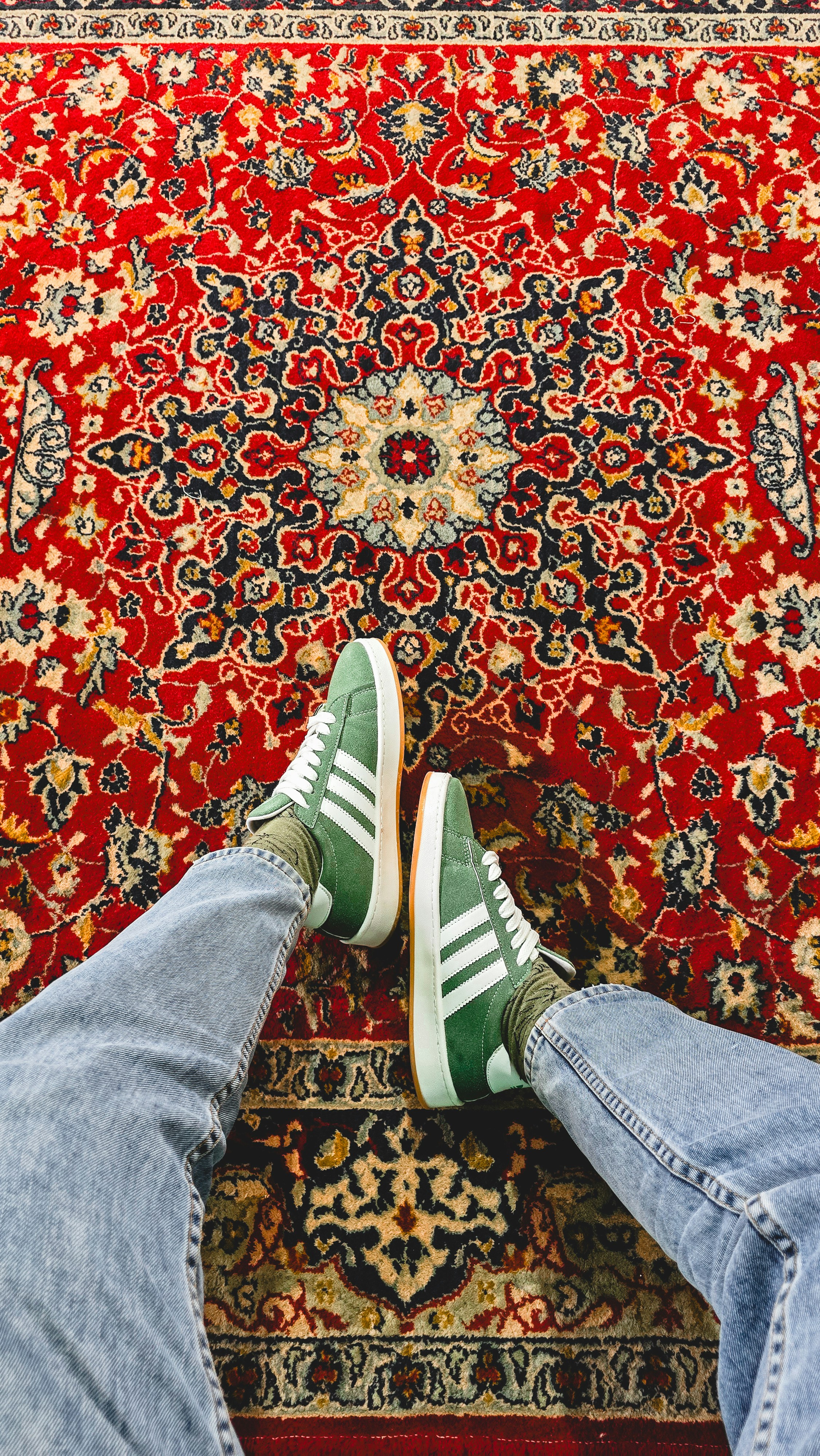 Eyewear and Carpet: A Tilted View of Green Sneakers on Red Fringed Pattern