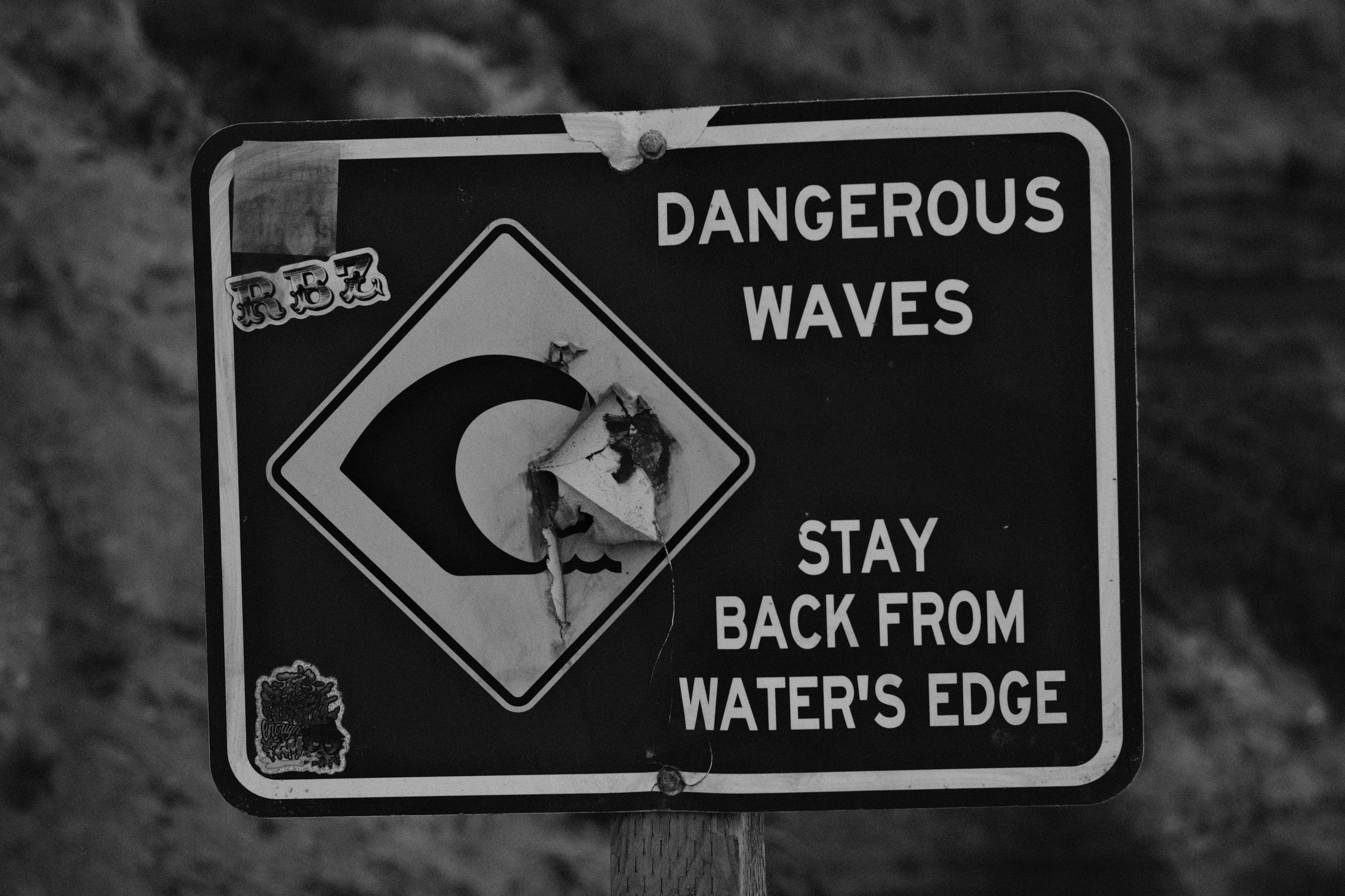 A black and white photo of a sign warning of dangerous waves photo ...