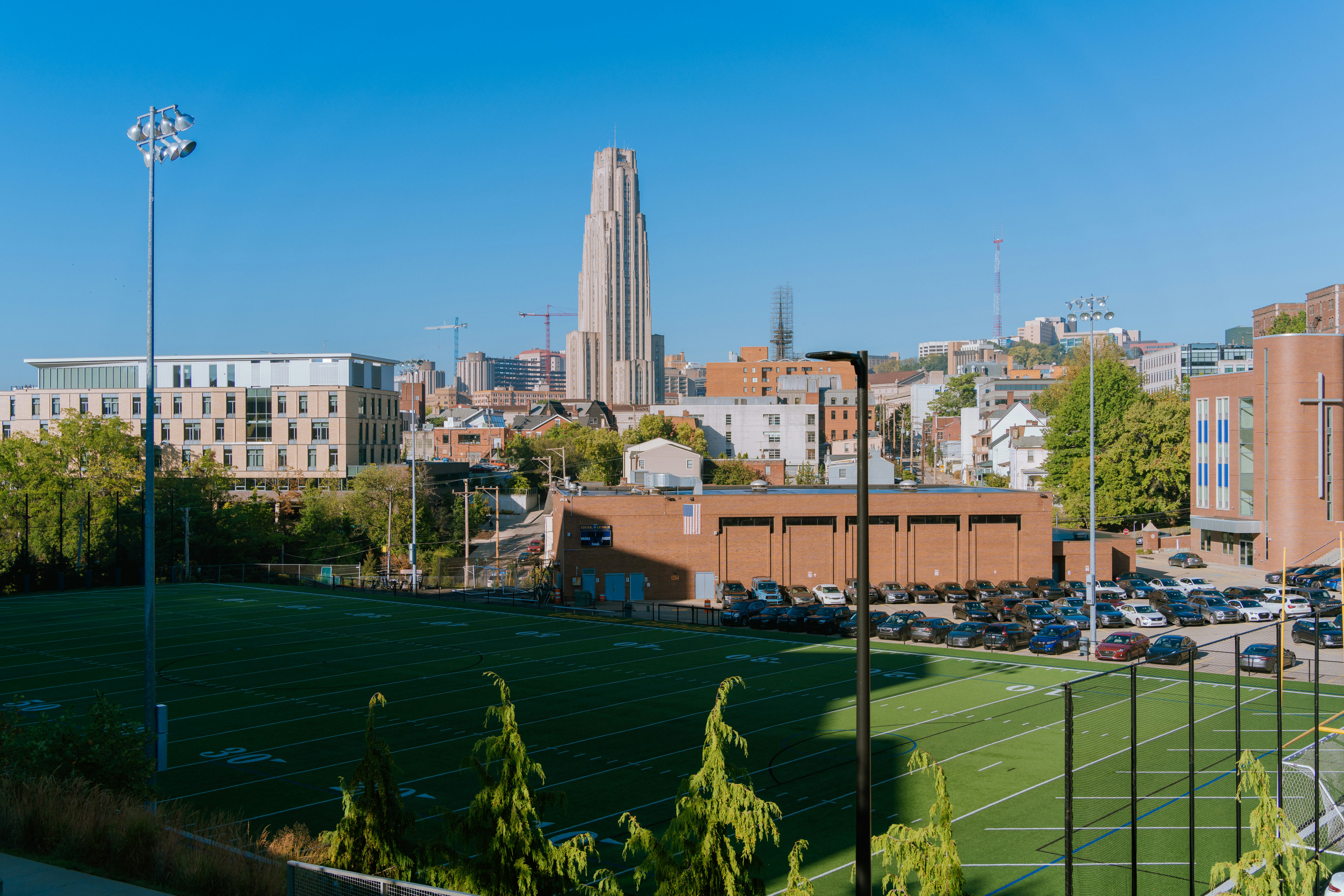 Towered Campus Crest: Football Field Beneath a Skyward Beacon