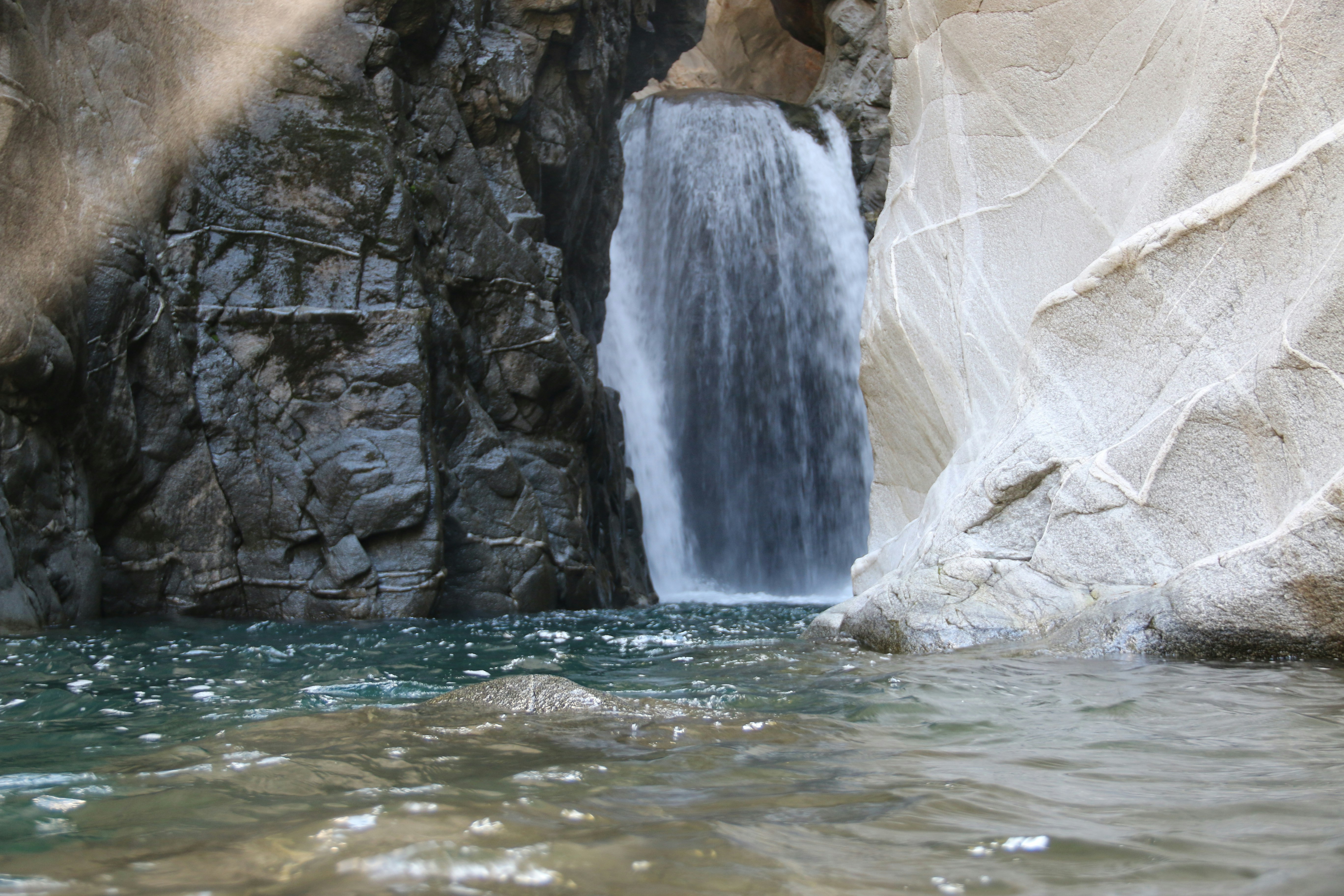 Silvery Cascade Between Dark Cliffs and Ice-White Rockface