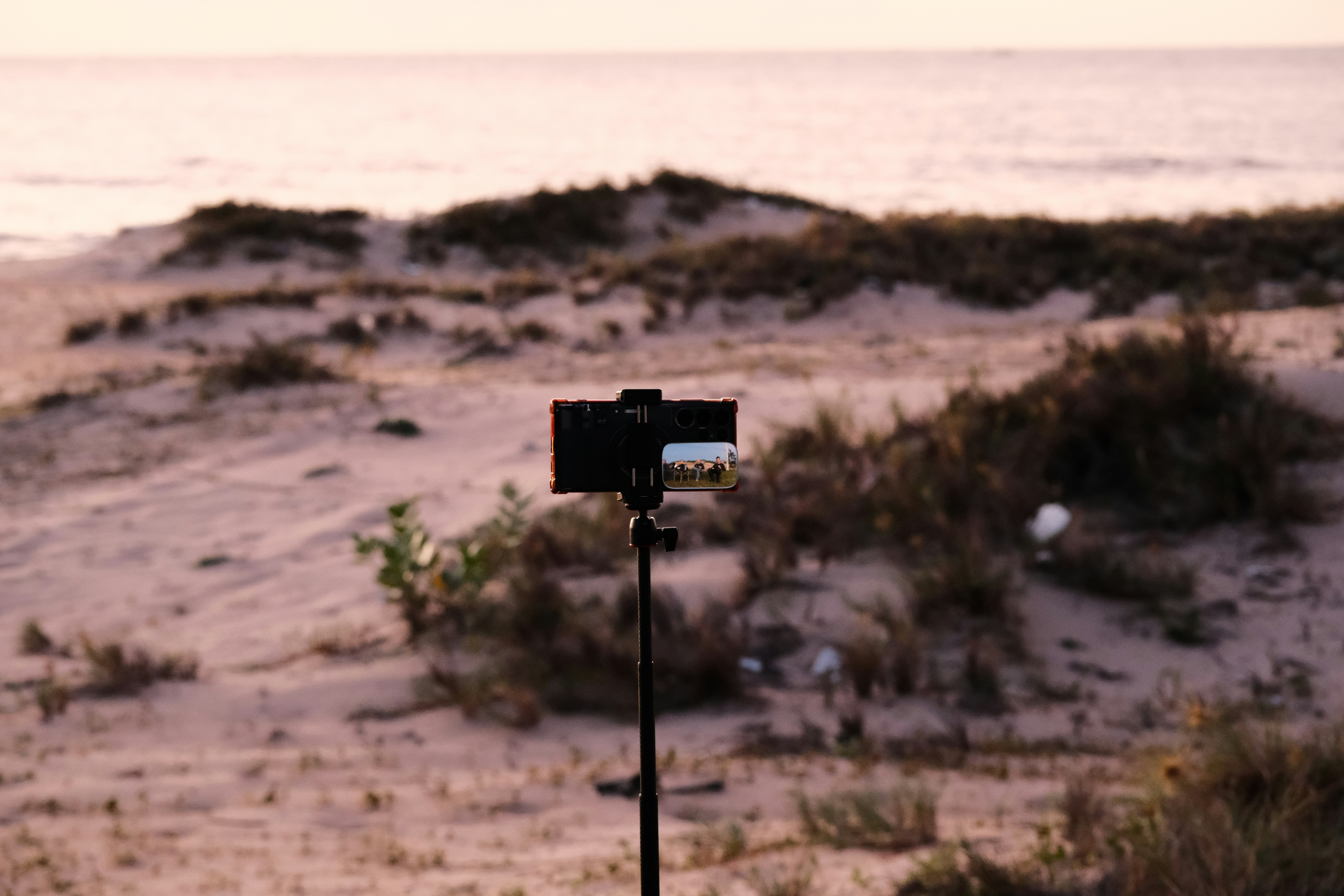 Dusk Watcher on the Beach: A lone camera perched on a post overlooking the sea