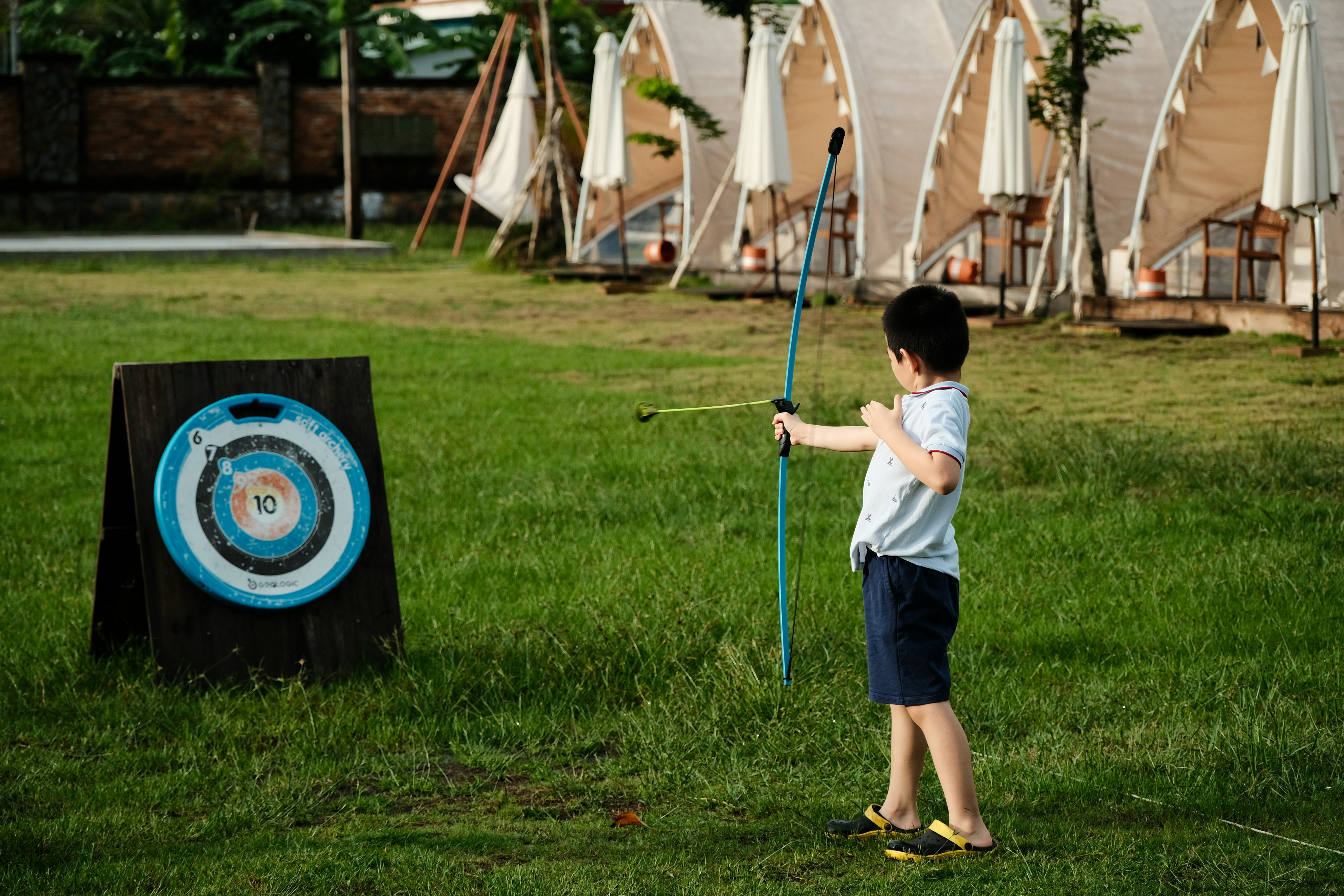 A young boy holding a bow and aiming an arrow photo – Free Human Image ...
