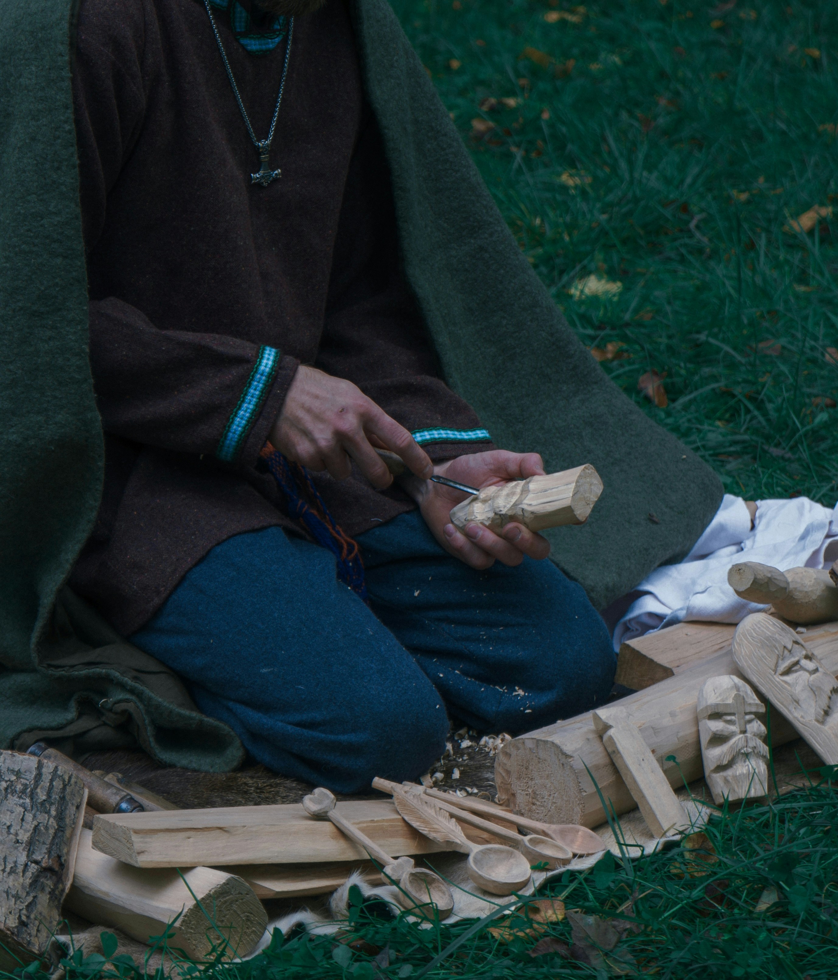 Carving Focus: Hands shaping driftwood beside a small woodpile