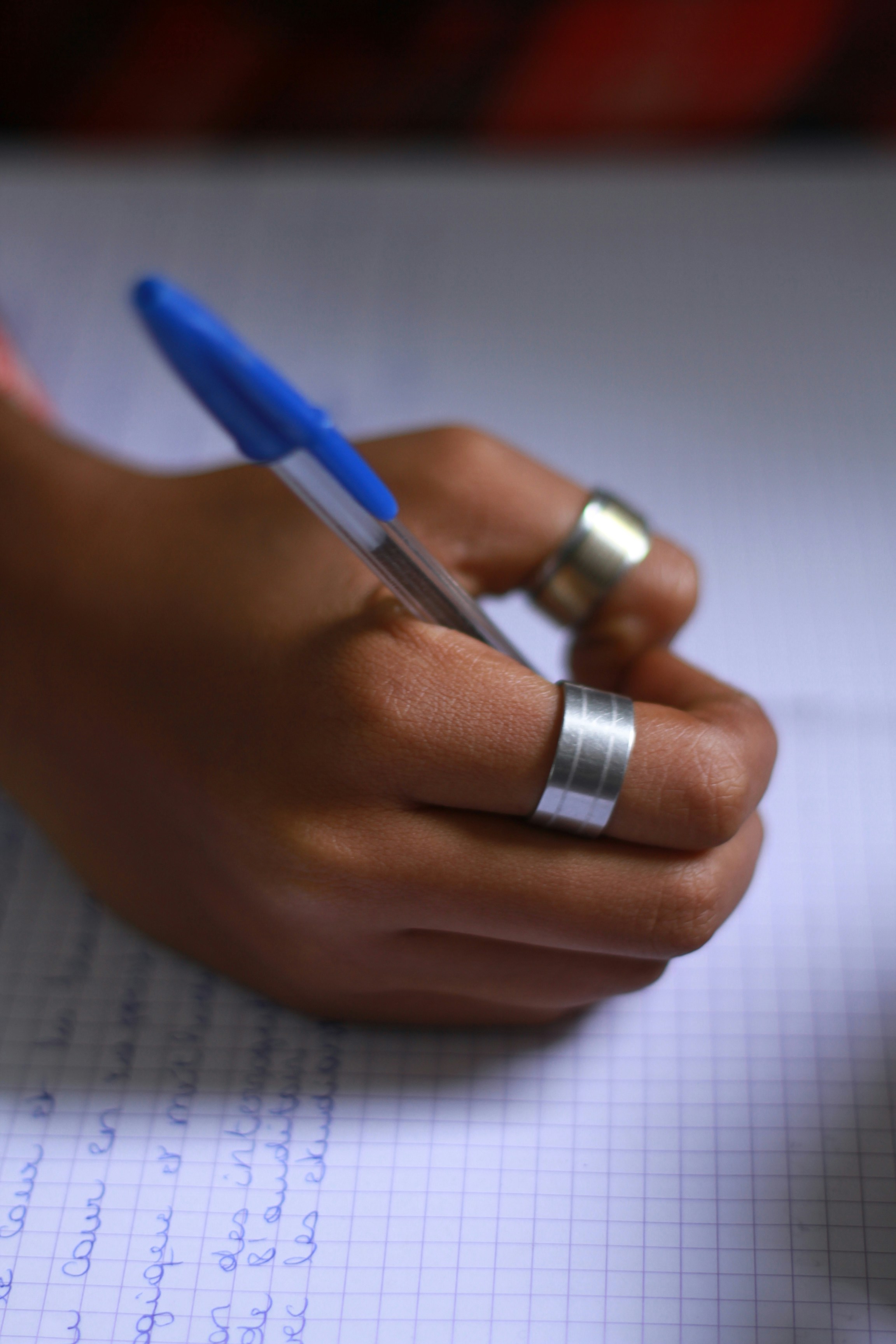 A person holding a pen and writing on a piece of paper photo – Free ...