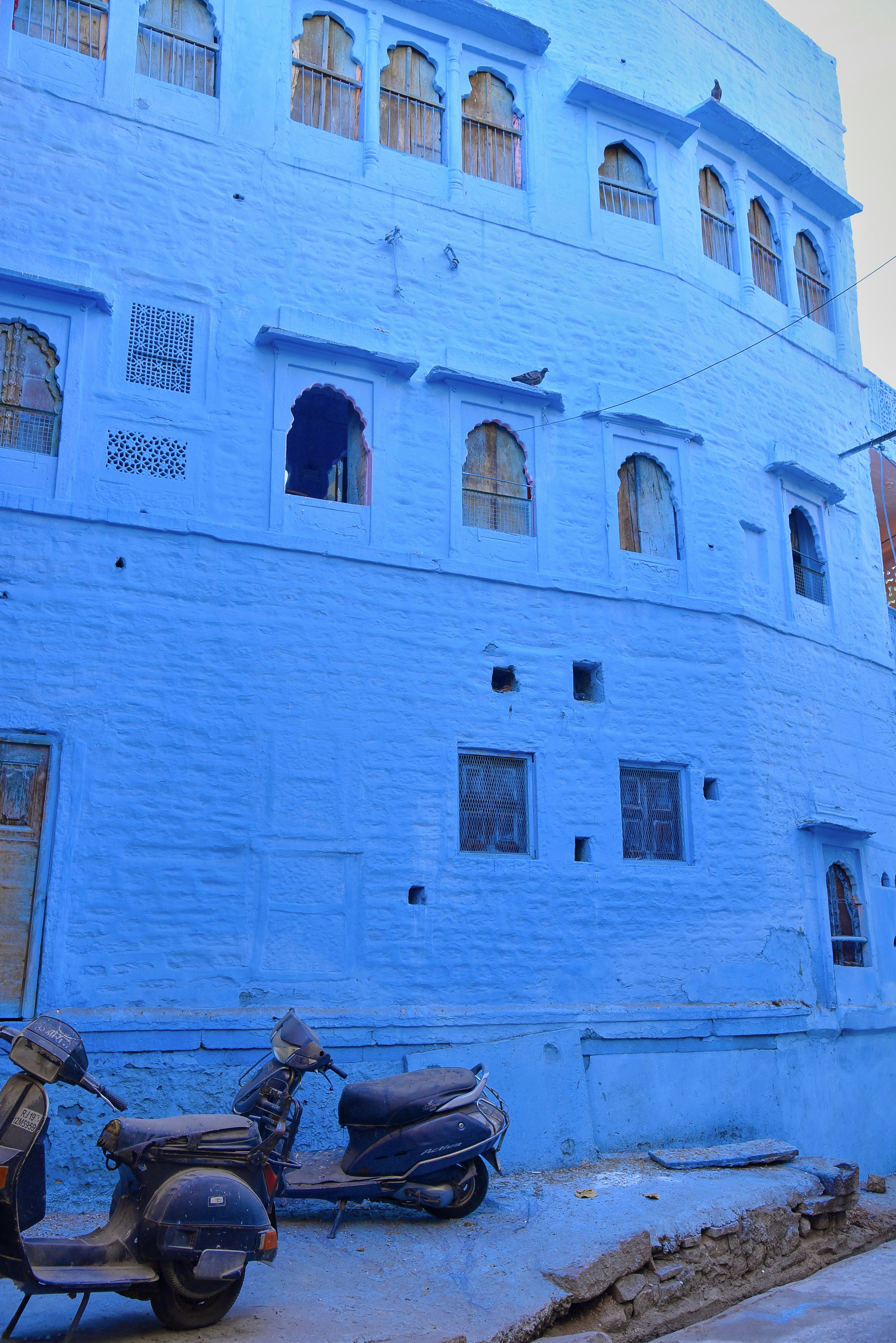 Indigo Facade: Scooters at the Foot of a Blue Arched Block