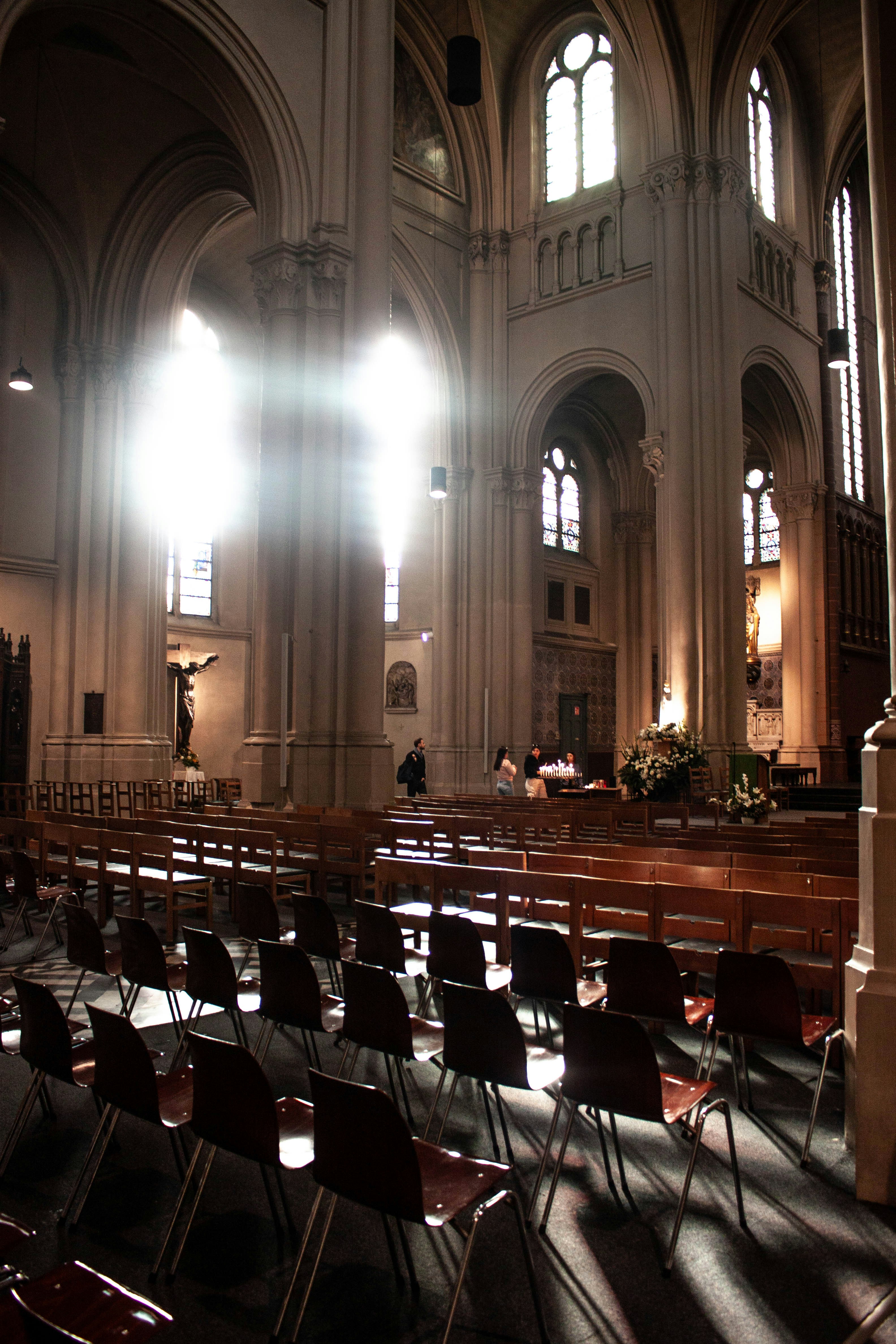 A church filled with lots of pews next to tall windows photo – Free ...