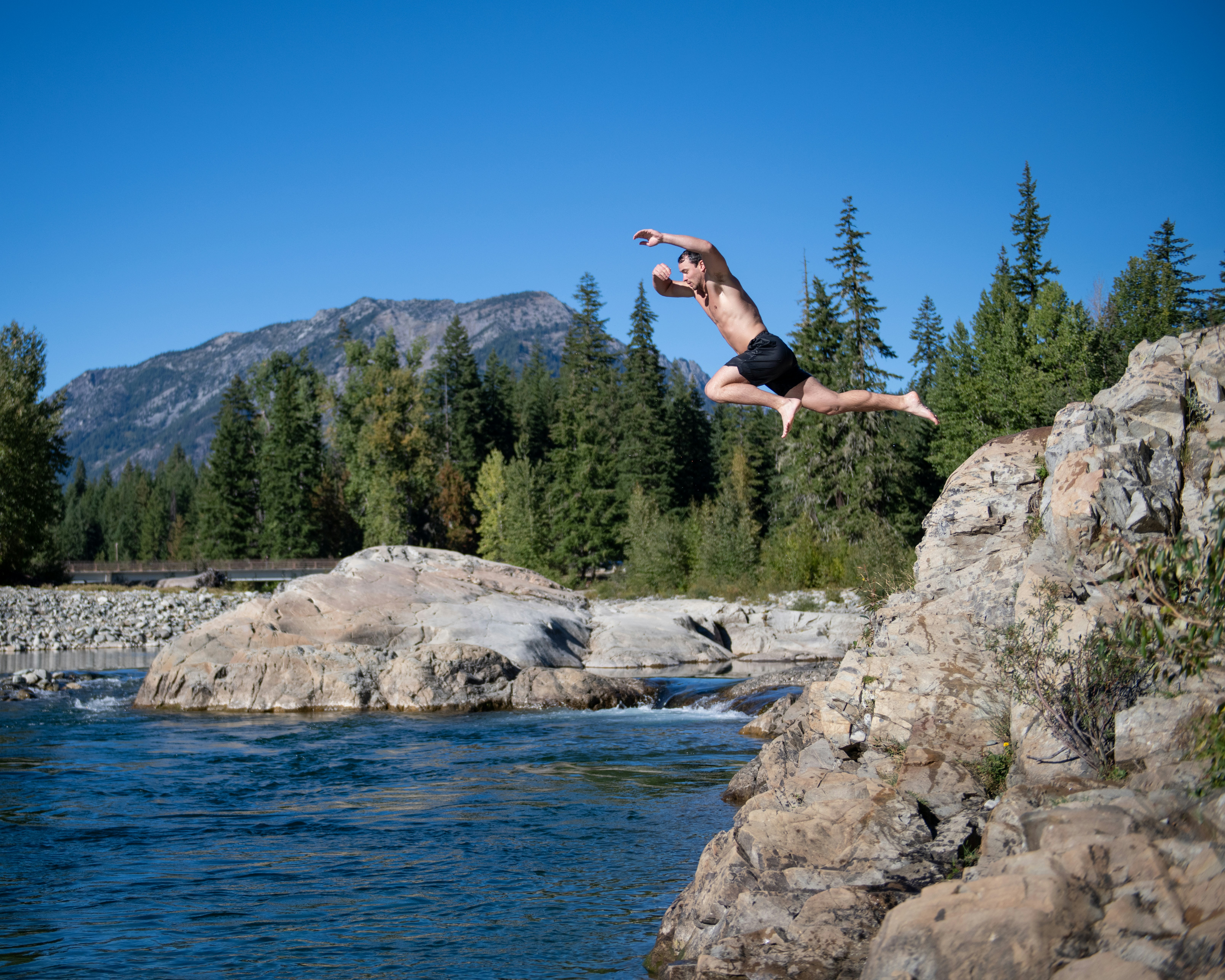 A man jumping off a cliff into a river photo – Free Travel Image on ...