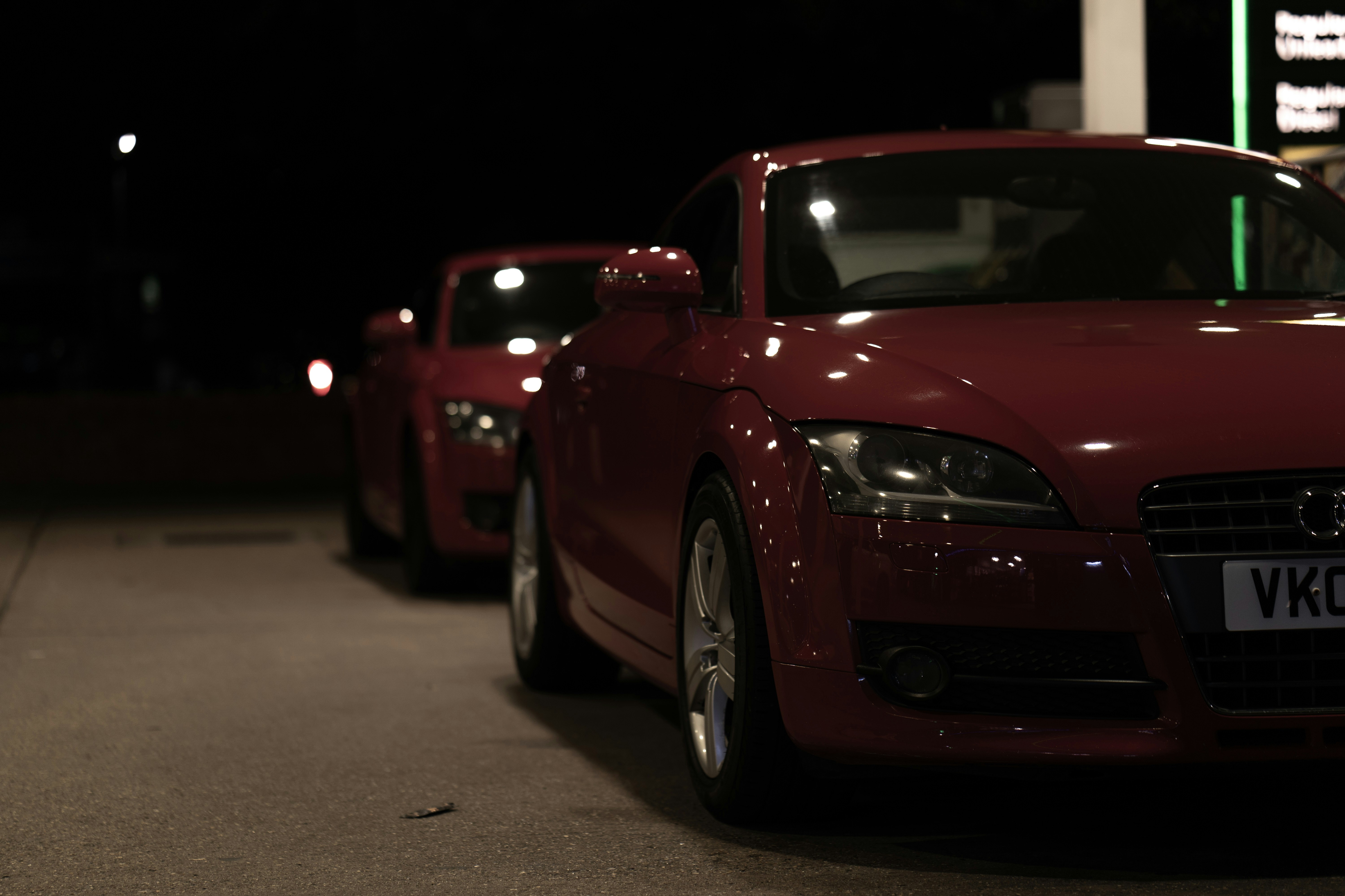 Midnight Lineup: Red Sedans Leading a Quiet Gas-Station Row