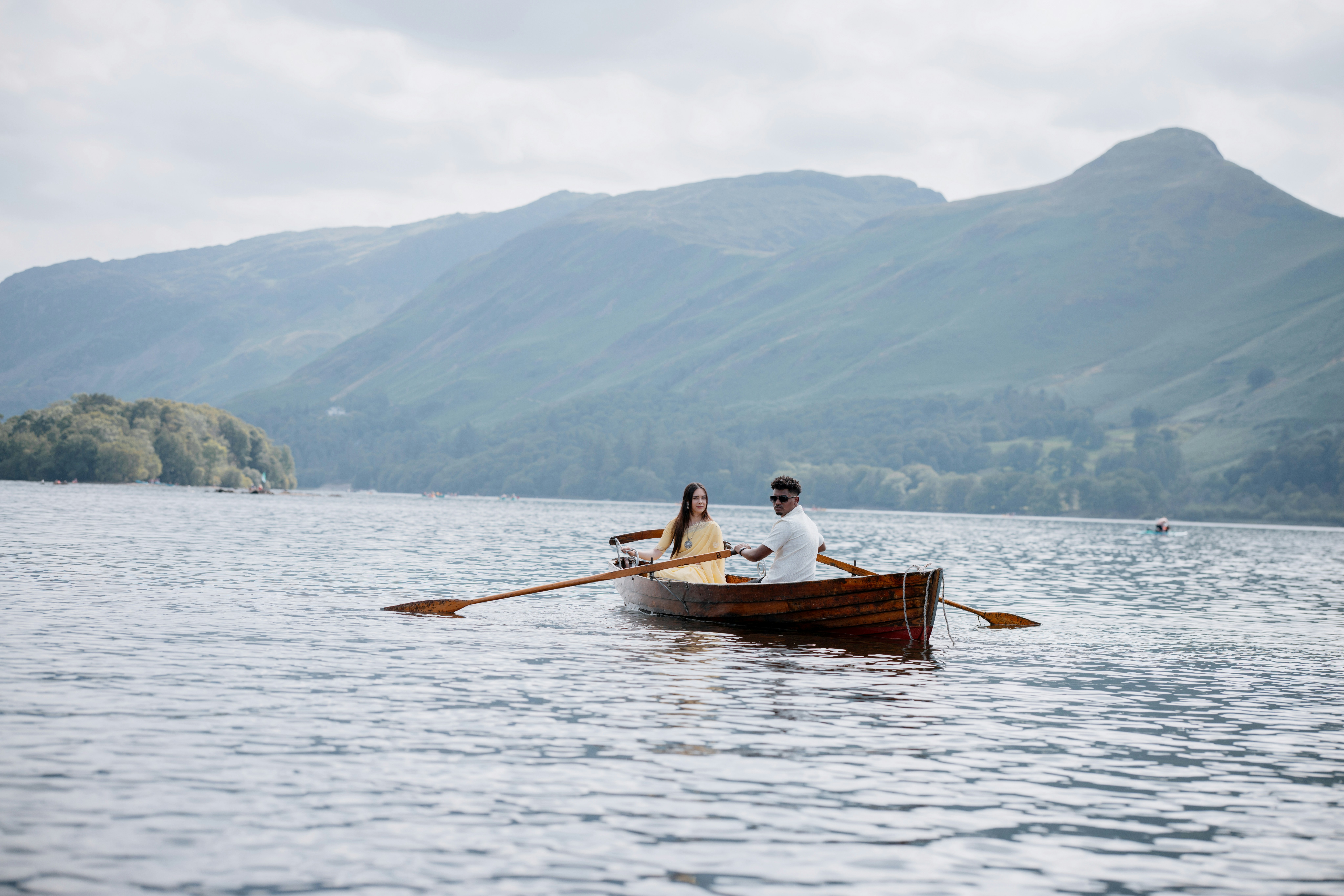 Rowing into Calm: A Couple glides across a mountain-fringed lake