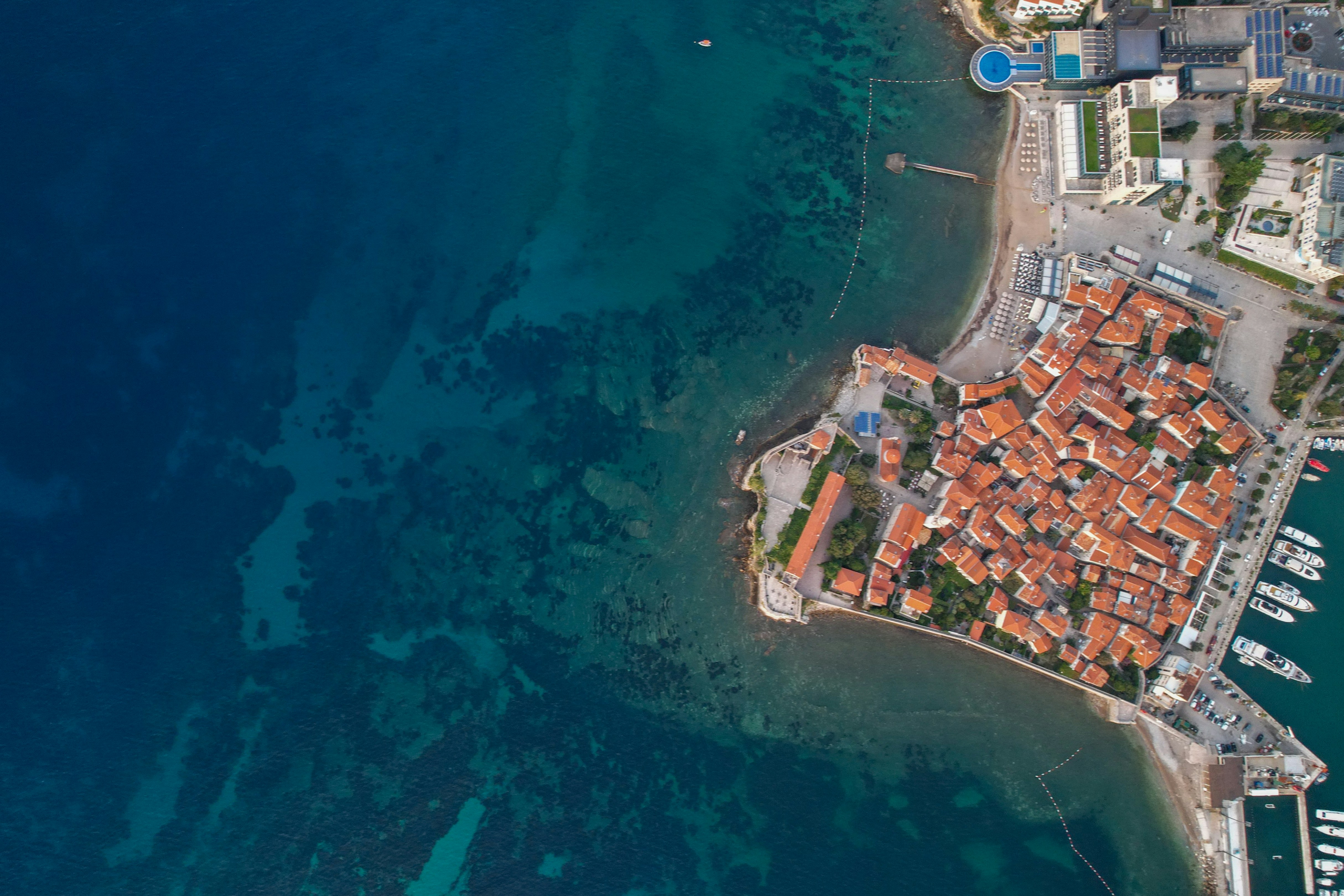 Aerial view of a picturesque coastal village nestled by the turquoise waters, showcasing a blend of vibrant rooftops and serene marinas.