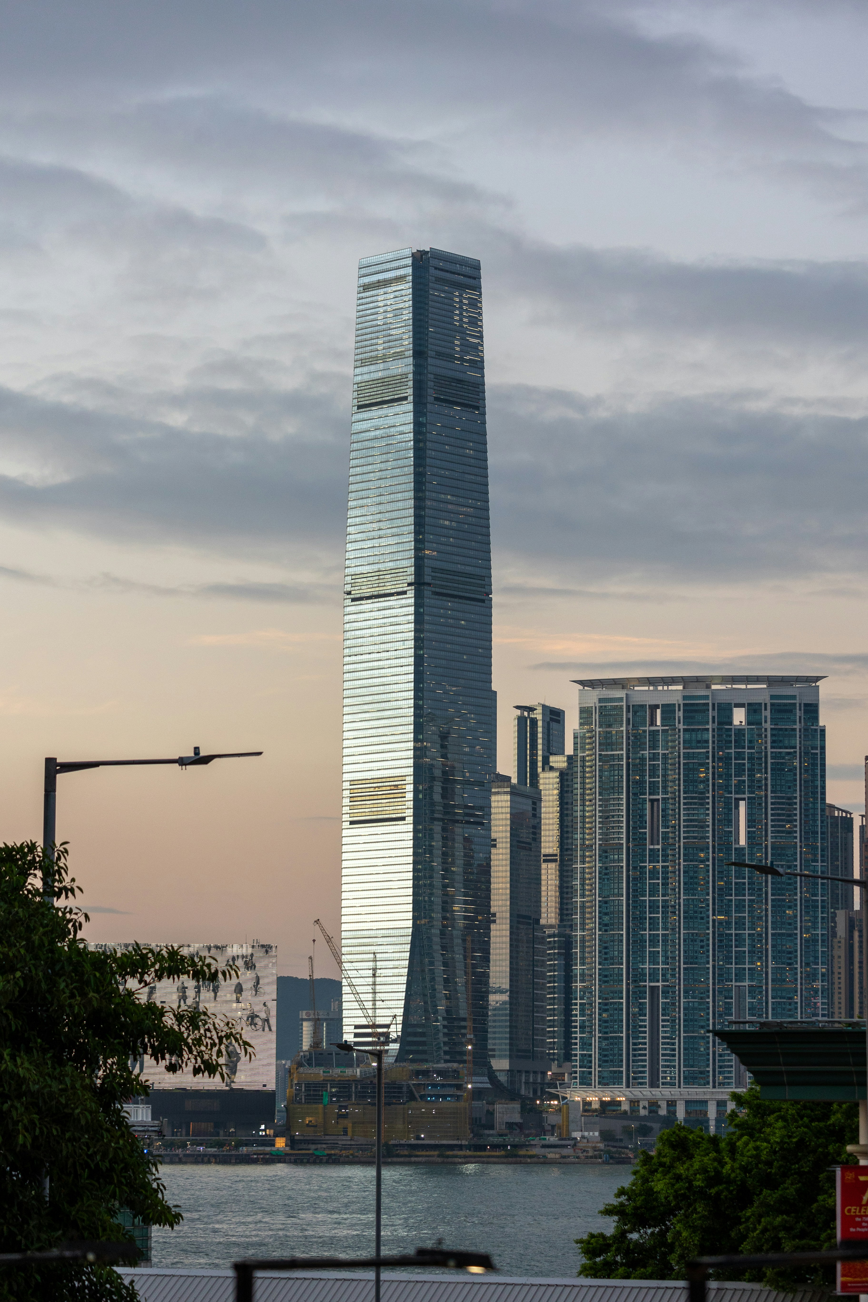 A tall skyscraper towering over a city next to a body of water photo ...