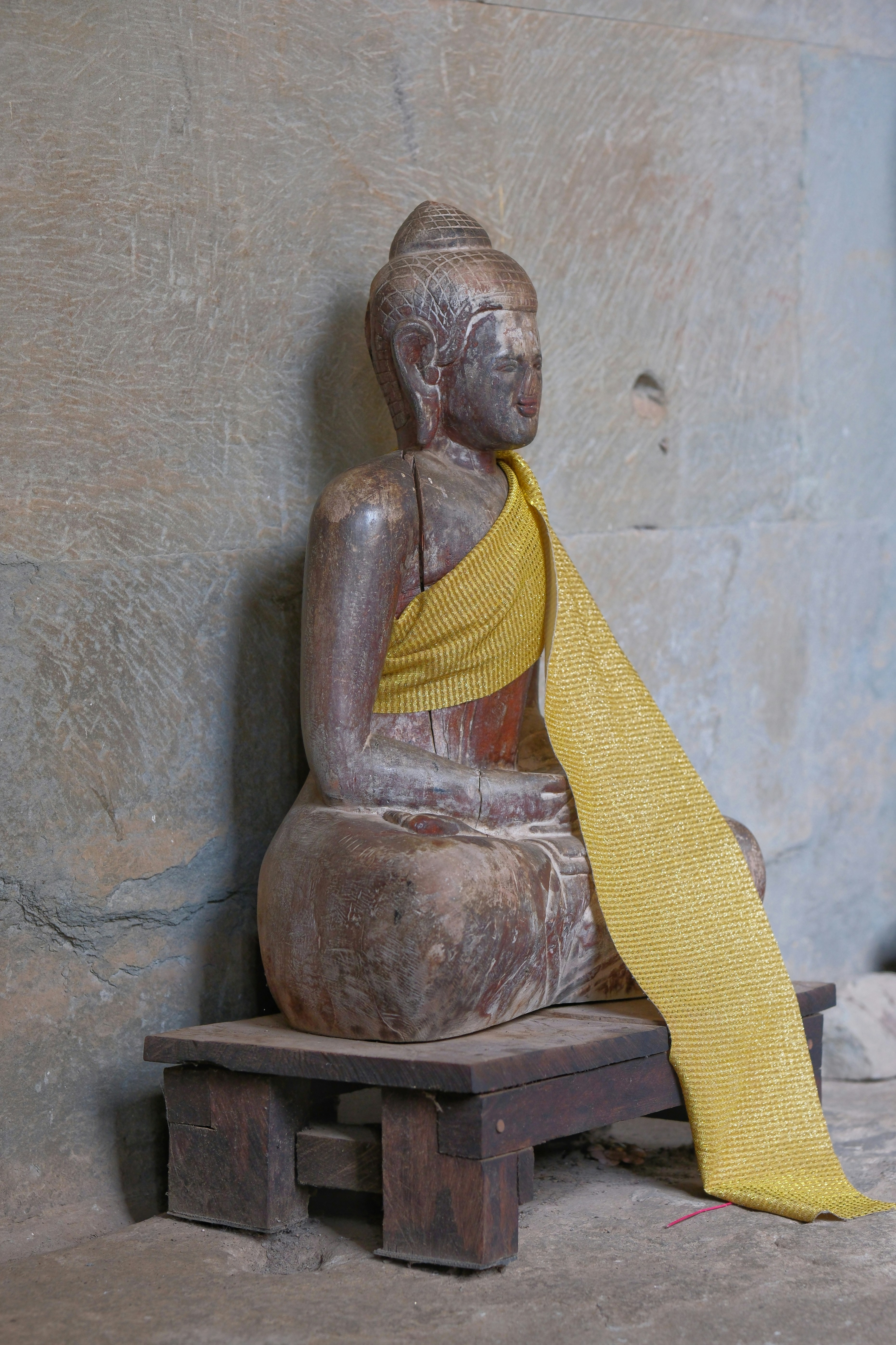 Golden Draped Buddha: Quiet Contemplation by a Stone Wall