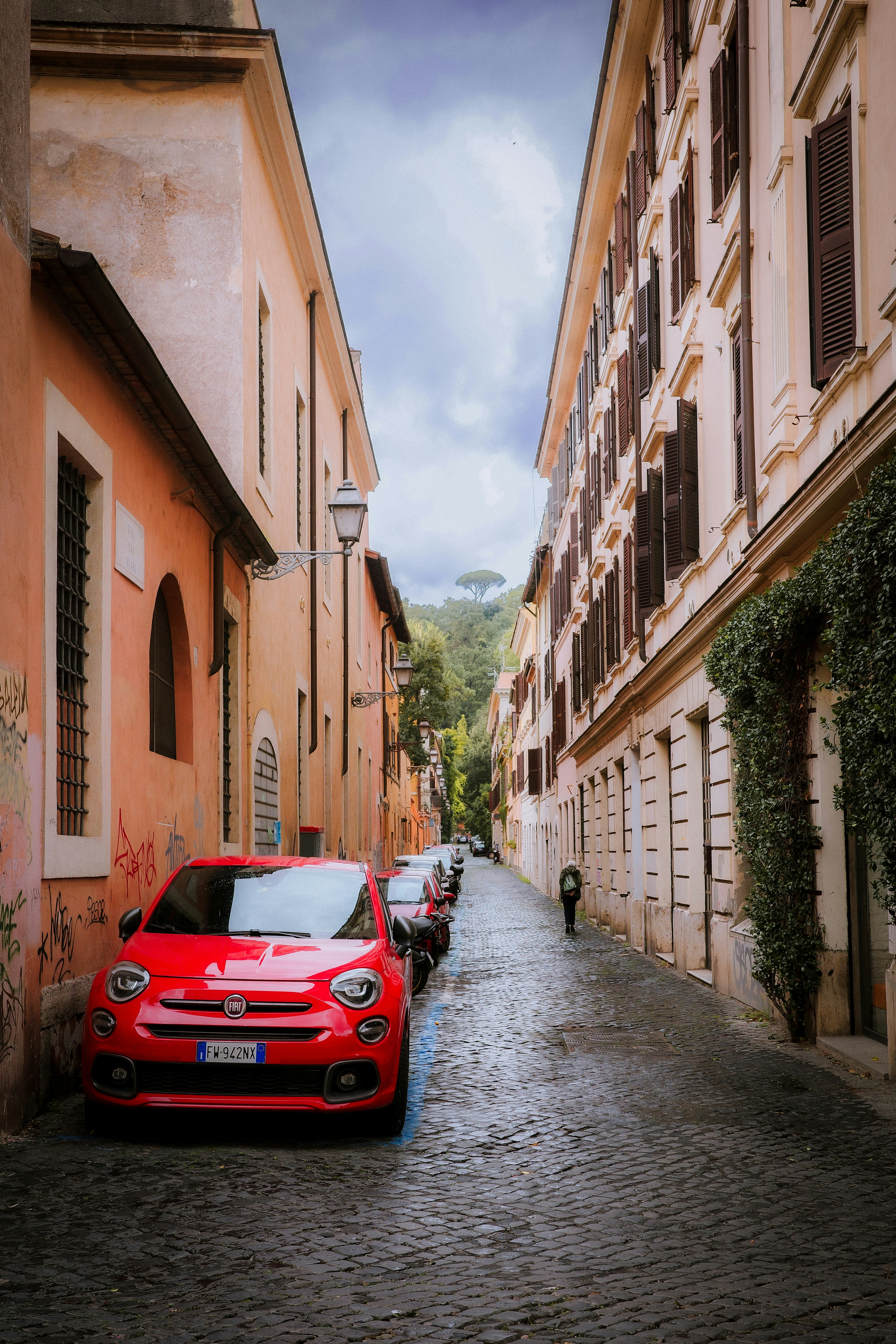 Red Fiat on a Cobblestone Alley Between Sunlit Façades