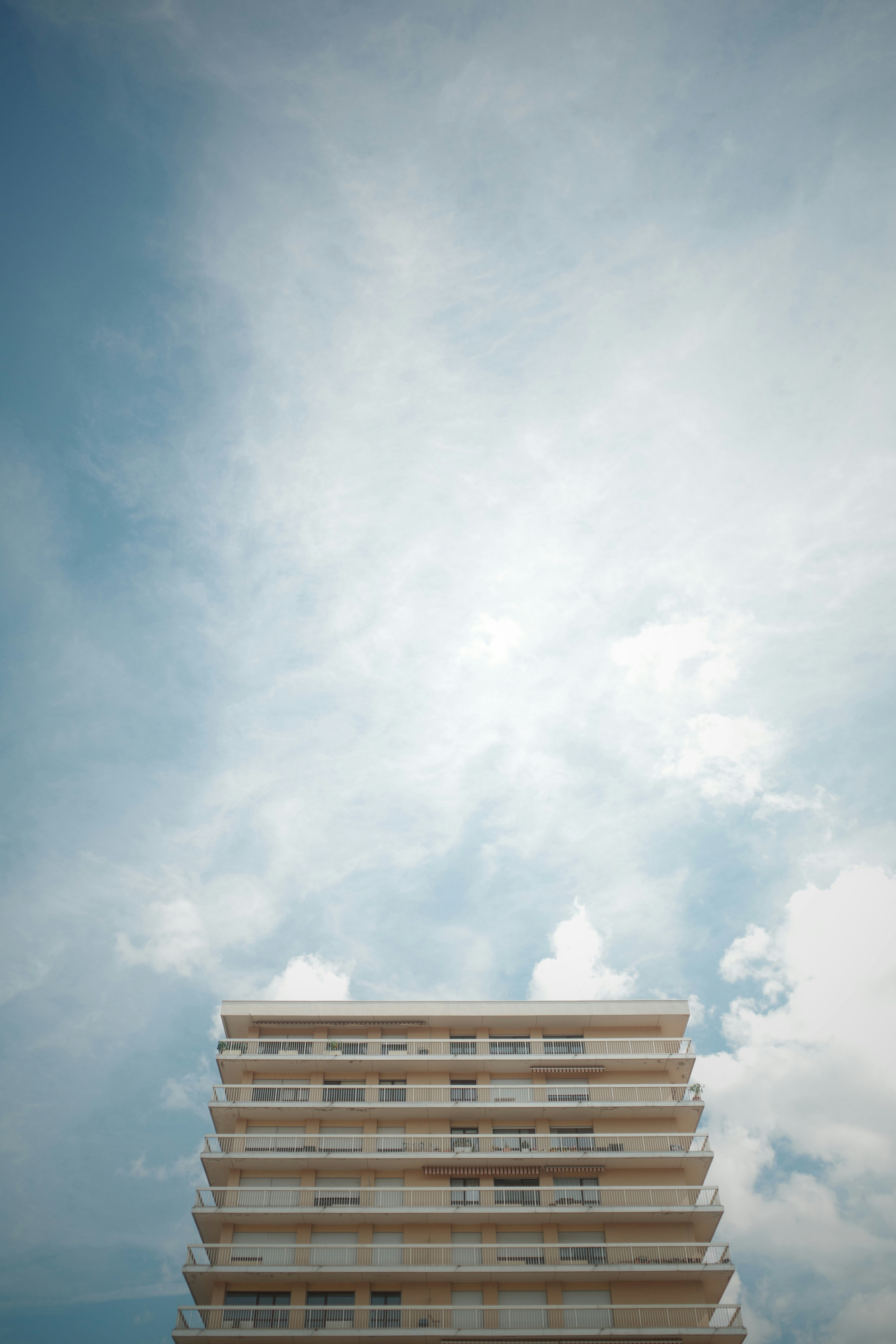 A multi-story building rises against a backdrop of soft, cloudy skies, highlighting contemporary architectural design.