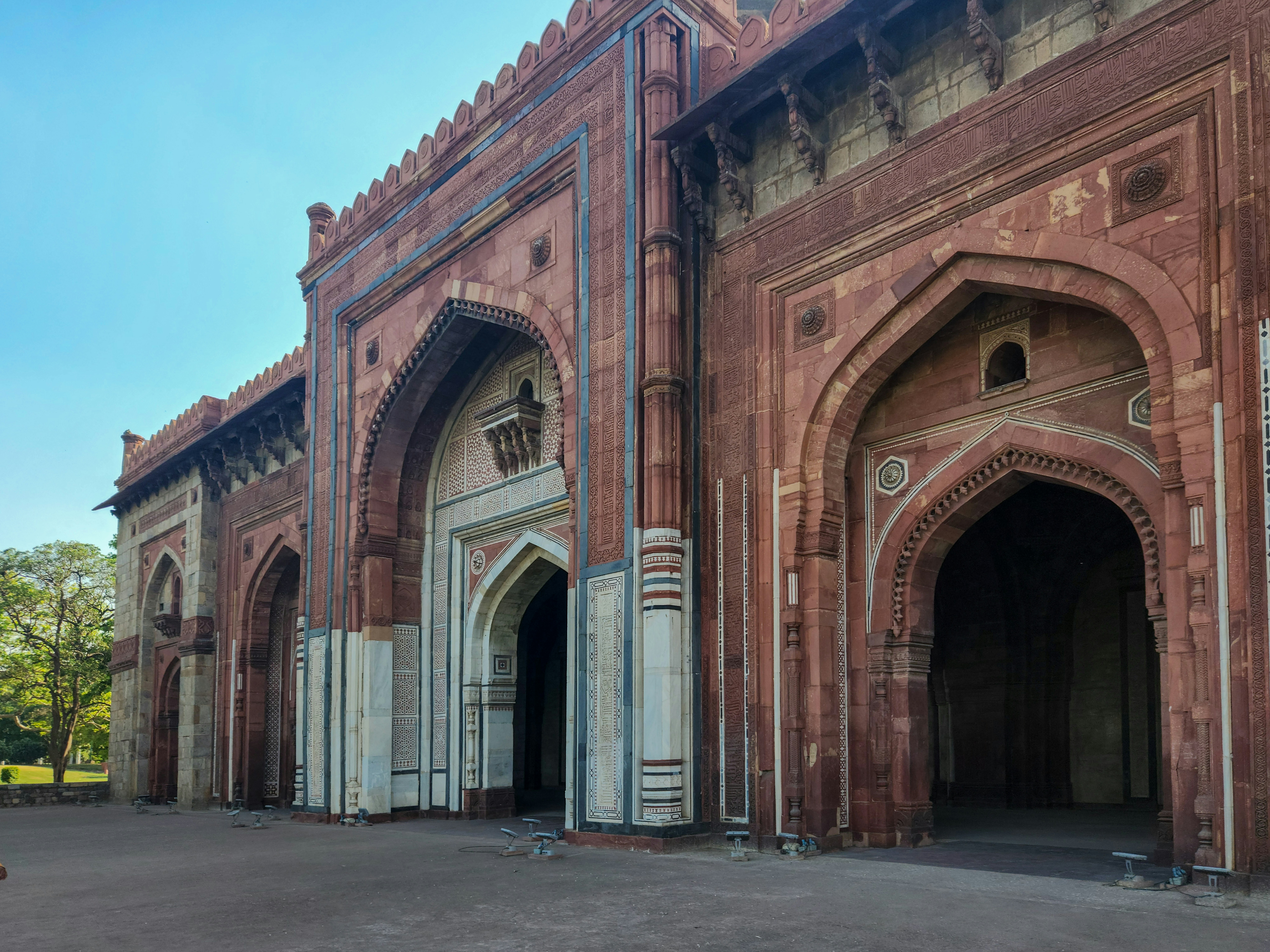 Intricate sandstone arches of Quila-i-Kuhna Mosque in Delhi showcase Indo-Islamic architecture.